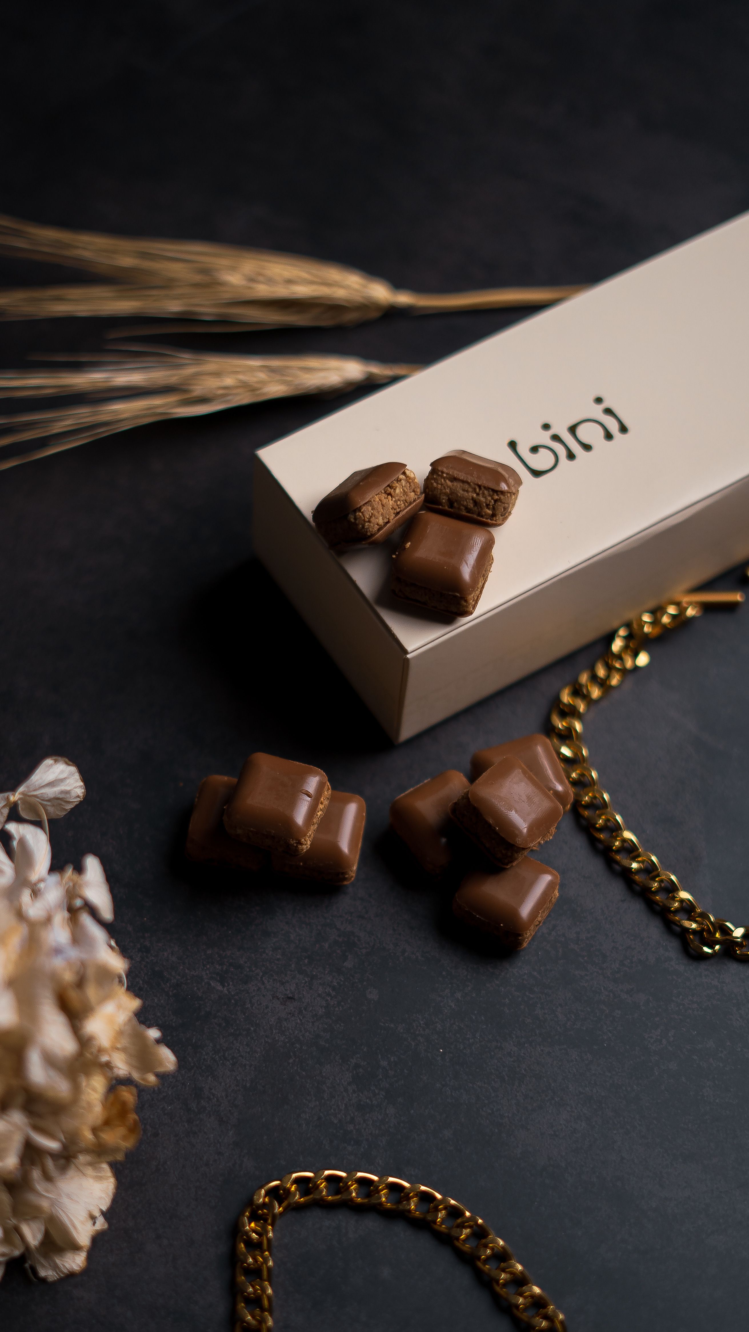 Chocolate Pieces Lying on White Box next to Elegant Gold Chains · Free ...