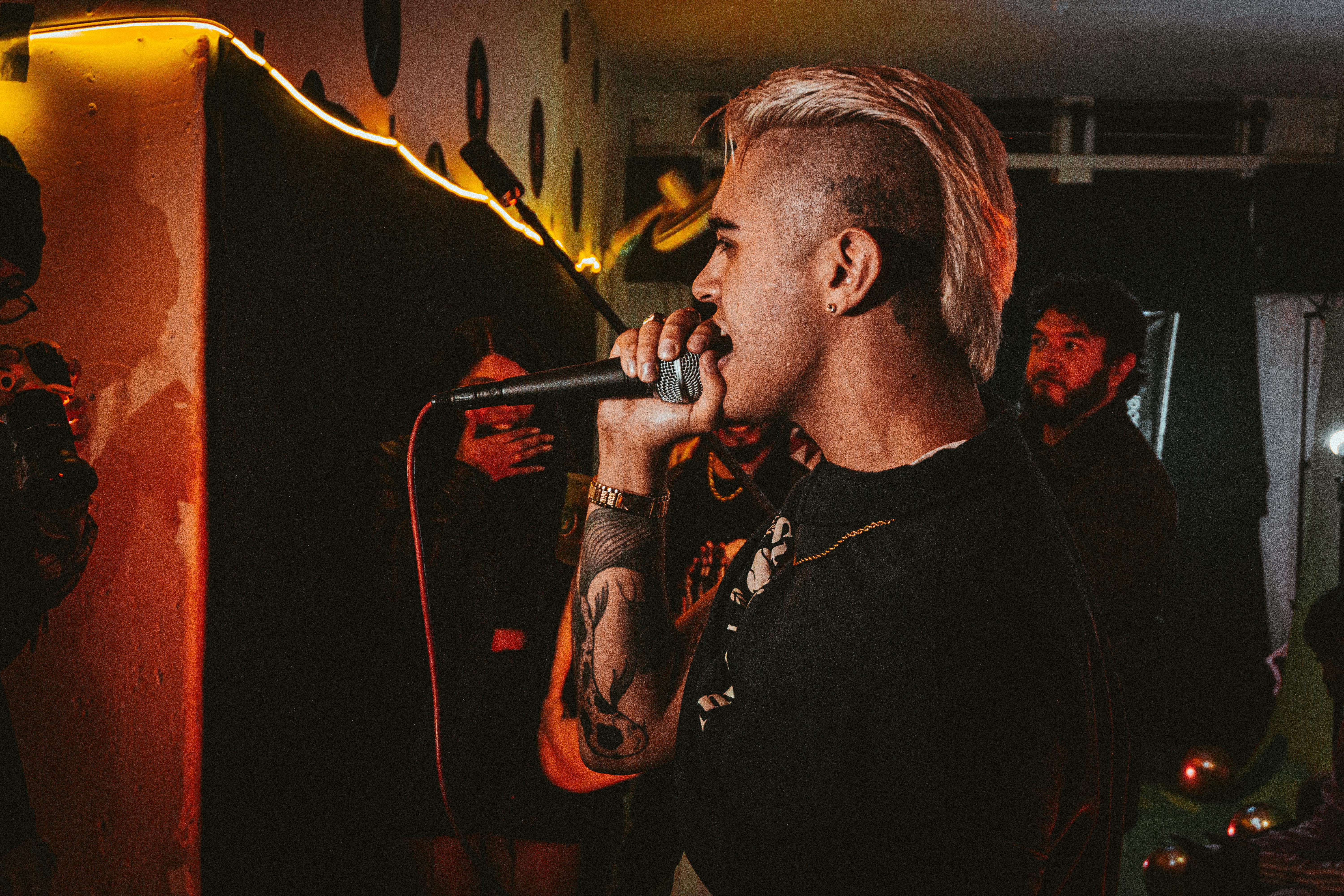 Man with Shaved Sides Singing into Microphone · Free Stock Photo