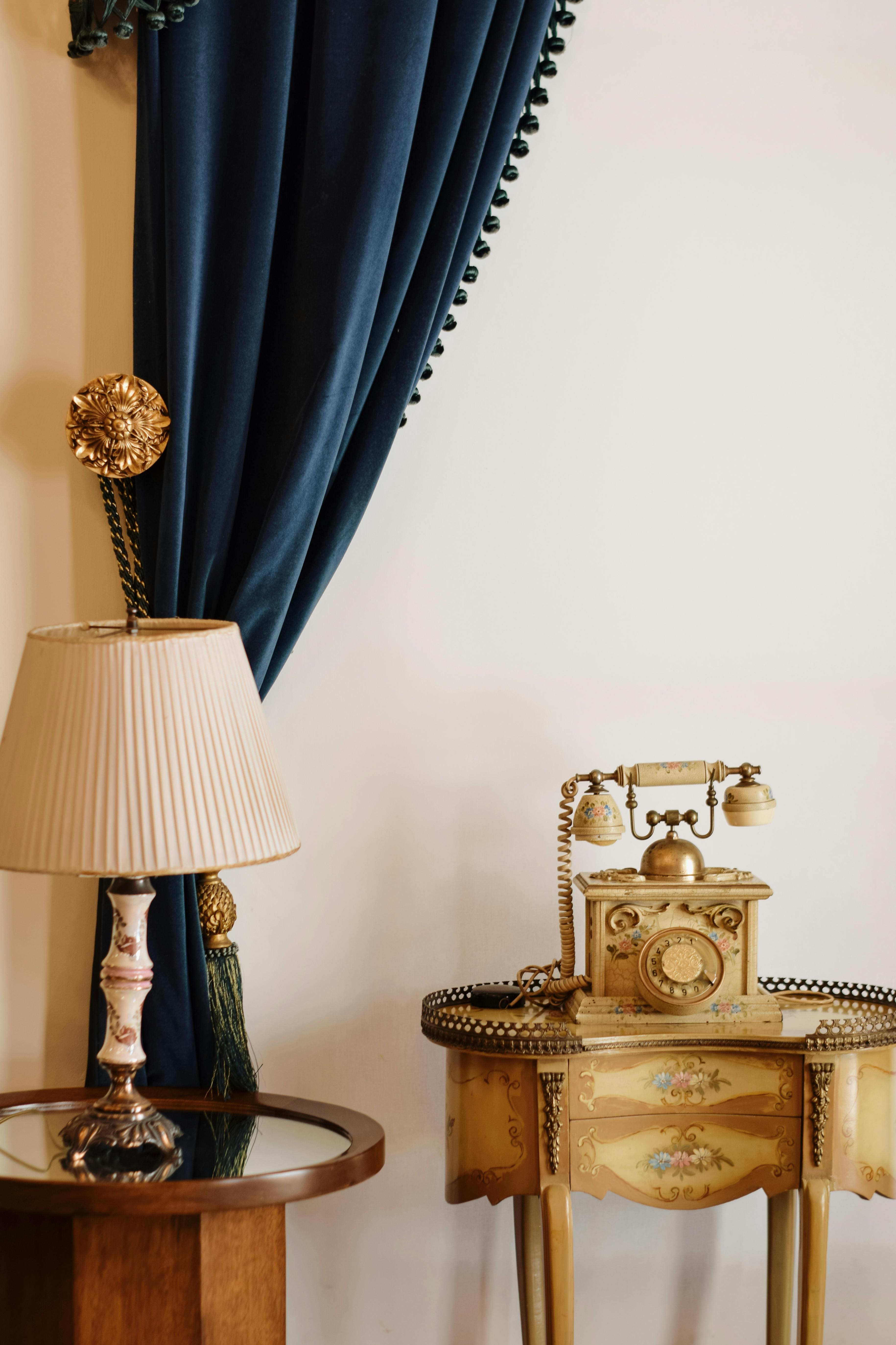 Ornate Rotary Dial Telephone on an Antique Table Next to a Lamp with a ...