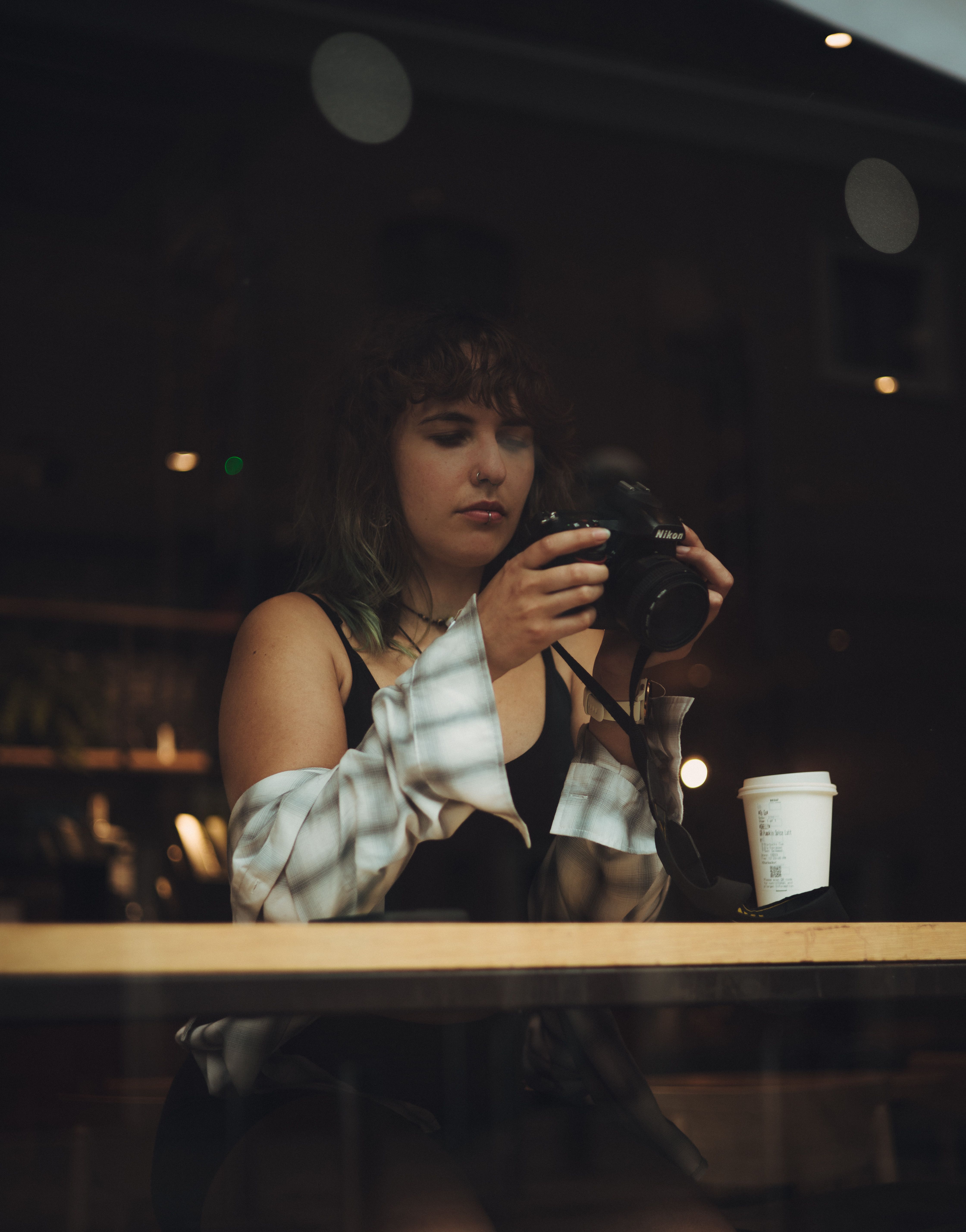 Woman Sitting with Camera by Table · Free Stock Photo
