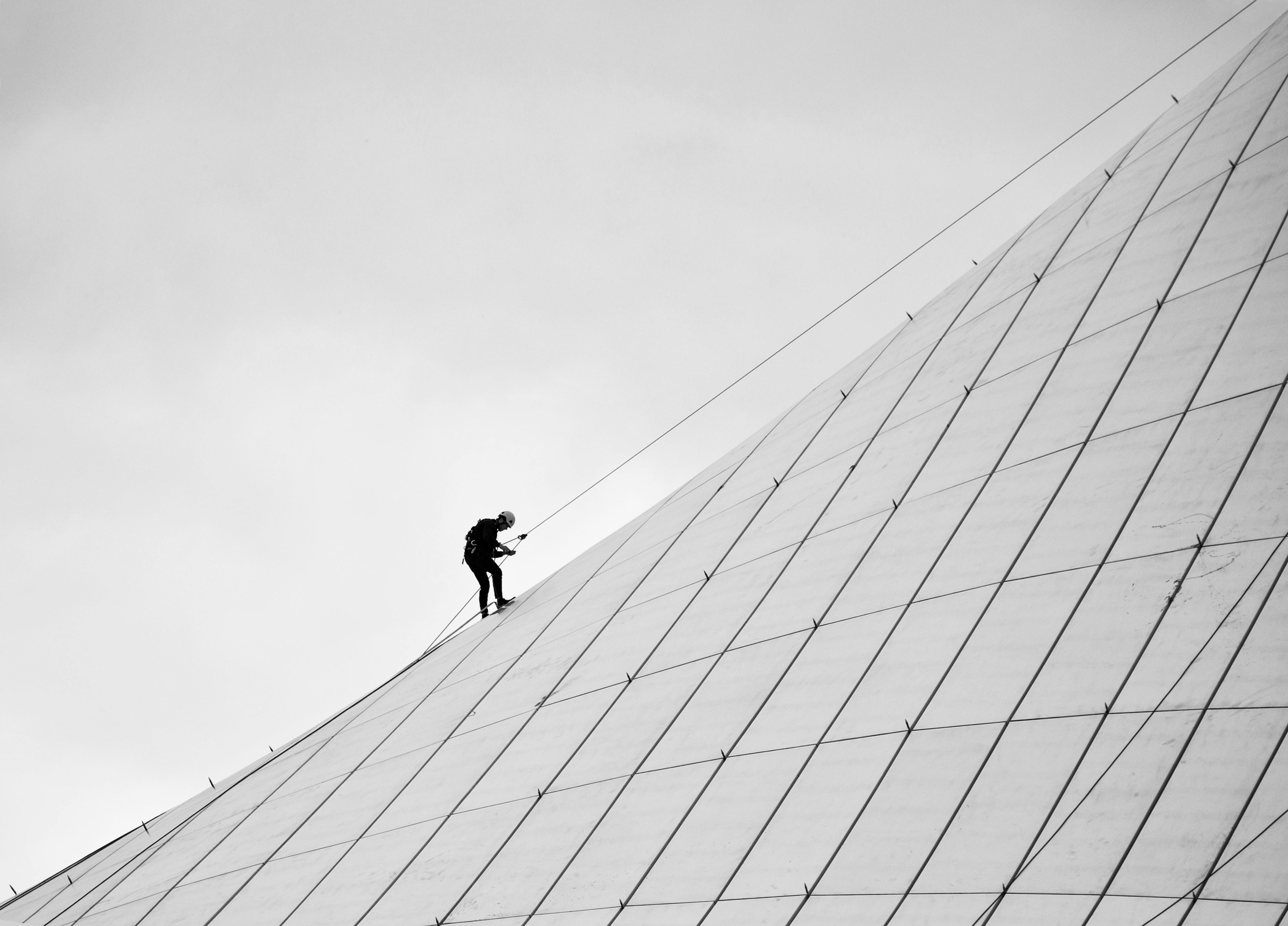 Man Climbing on a Modern Building in Black and White · Free Stock Photo