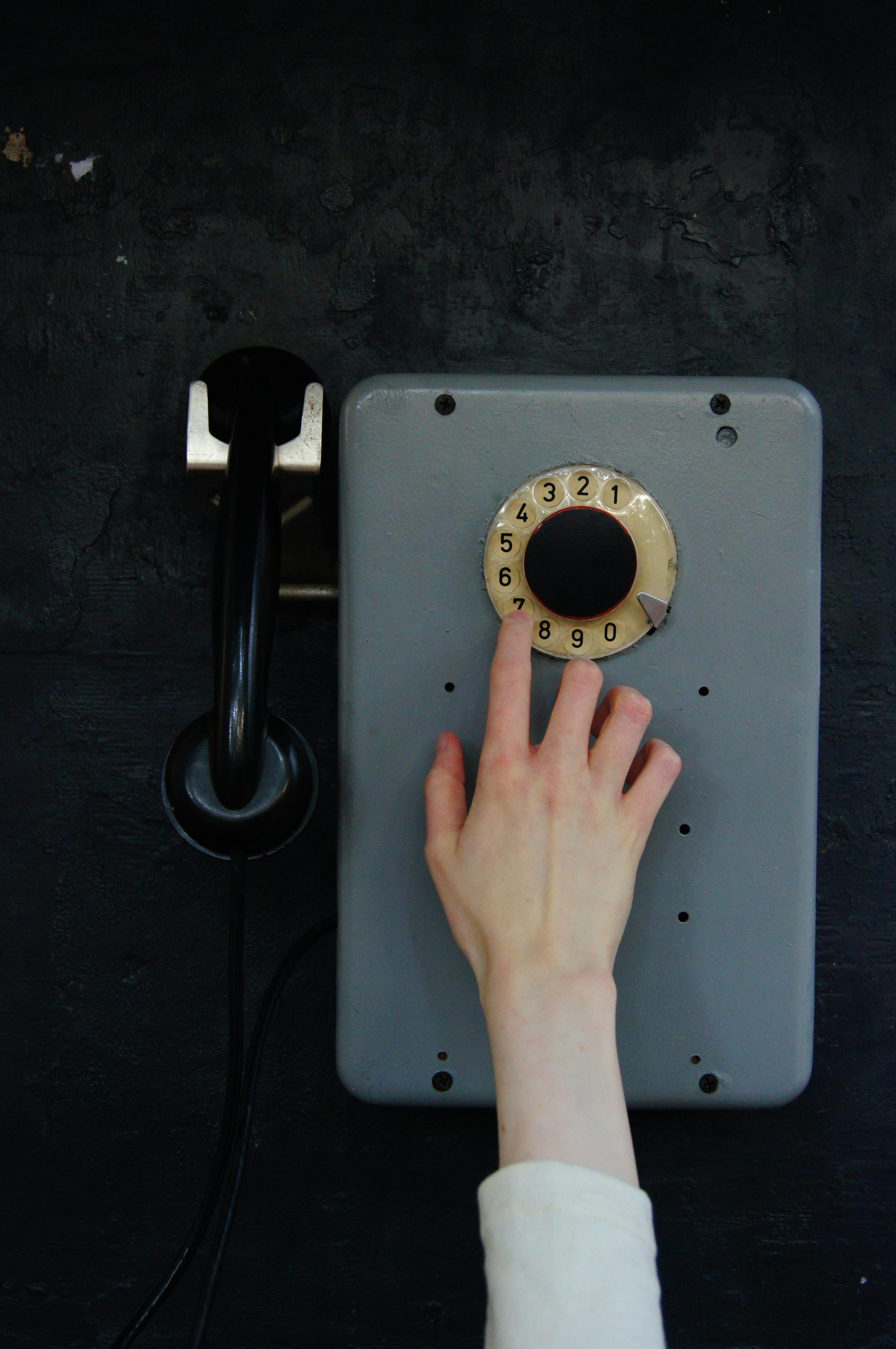 Woman Using Old Corded Phone Hanging on Wall · Free Stock Photo