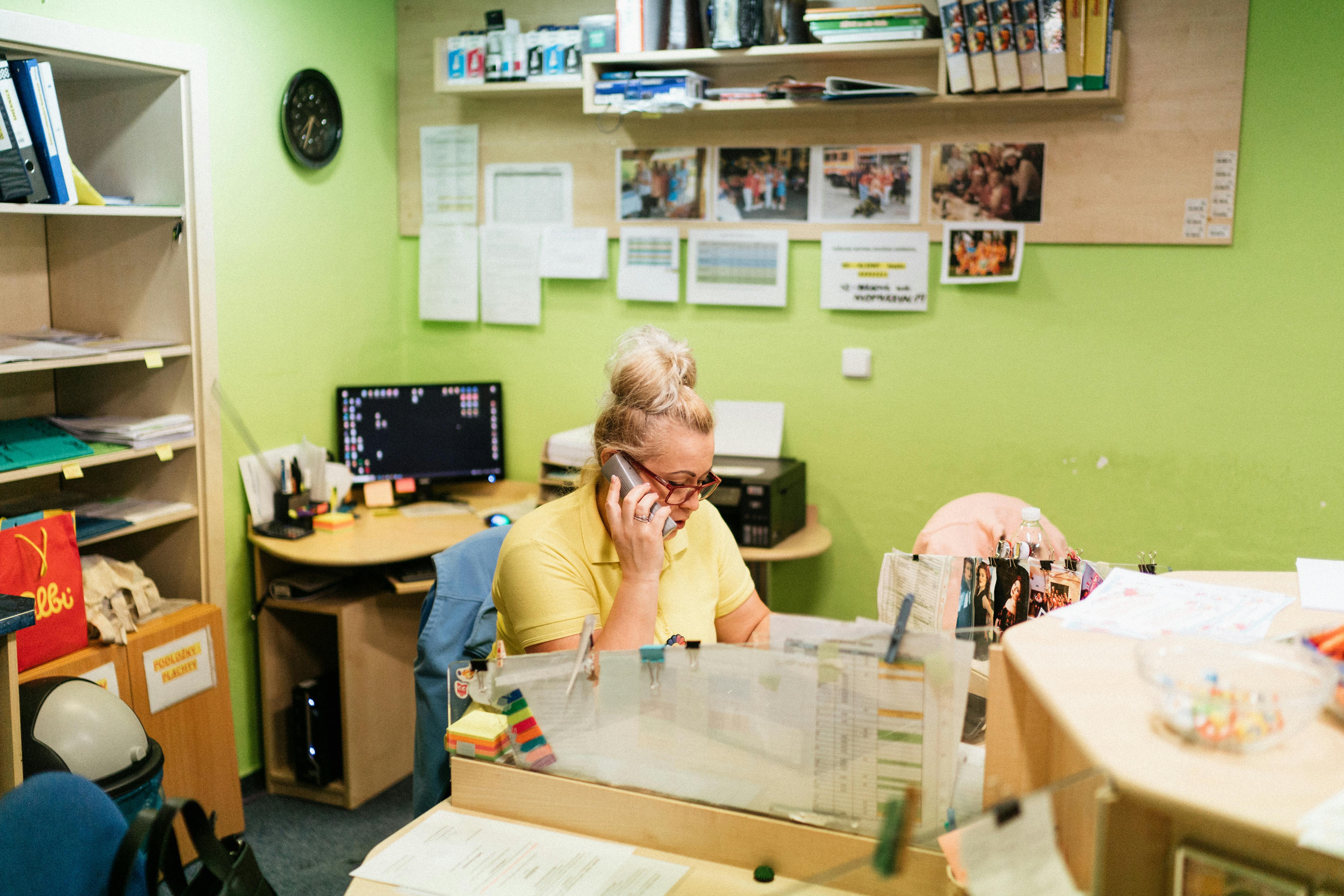 Woman Talking on Phone at Reception Desk in Nursing Home · Free Stock Photo