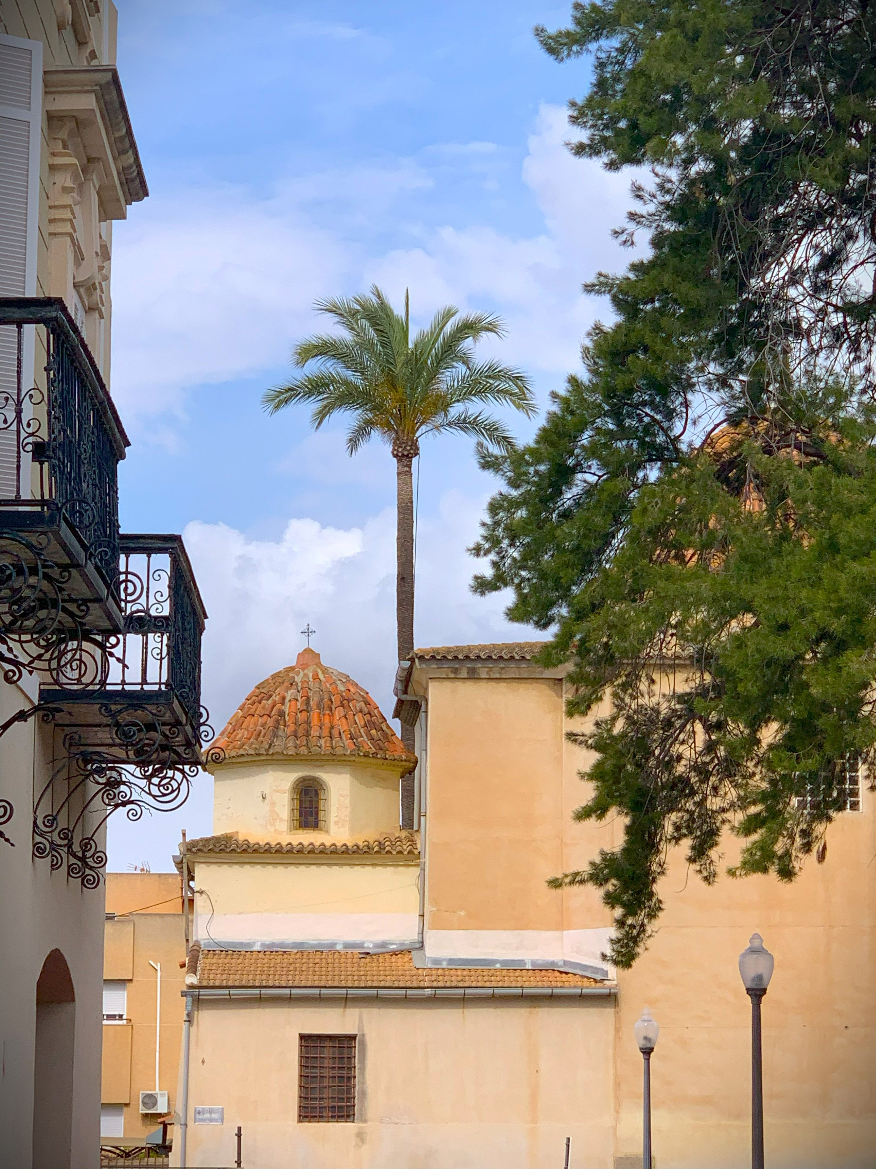 Church Tower behind Building Wall · Free Stock Photo