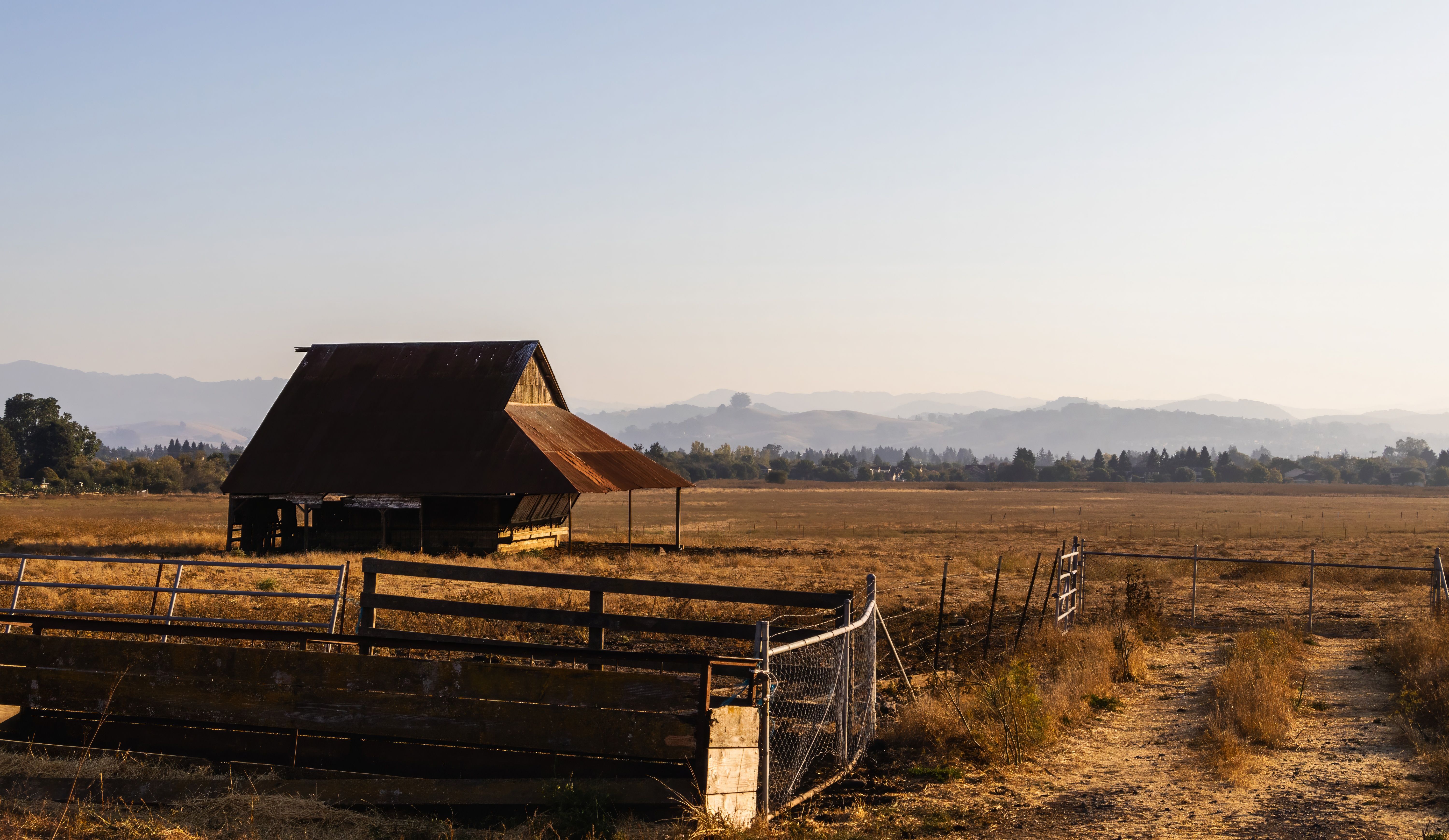 Wooden Barn with a Rusty Roof in the Field Surrounded by a Fence · Free ...