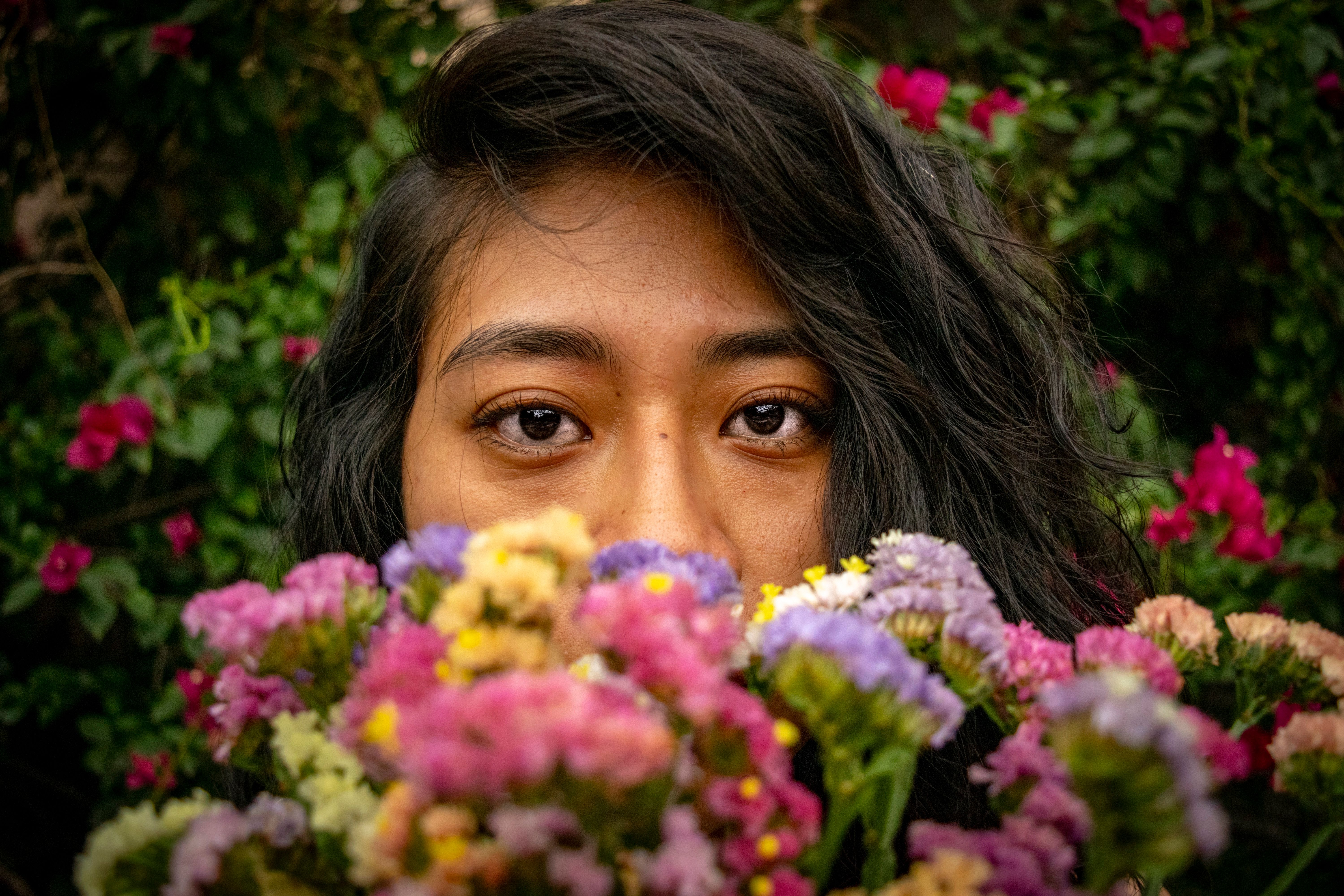 Brunette Woman Face behind Flowers · Free Stock Photo