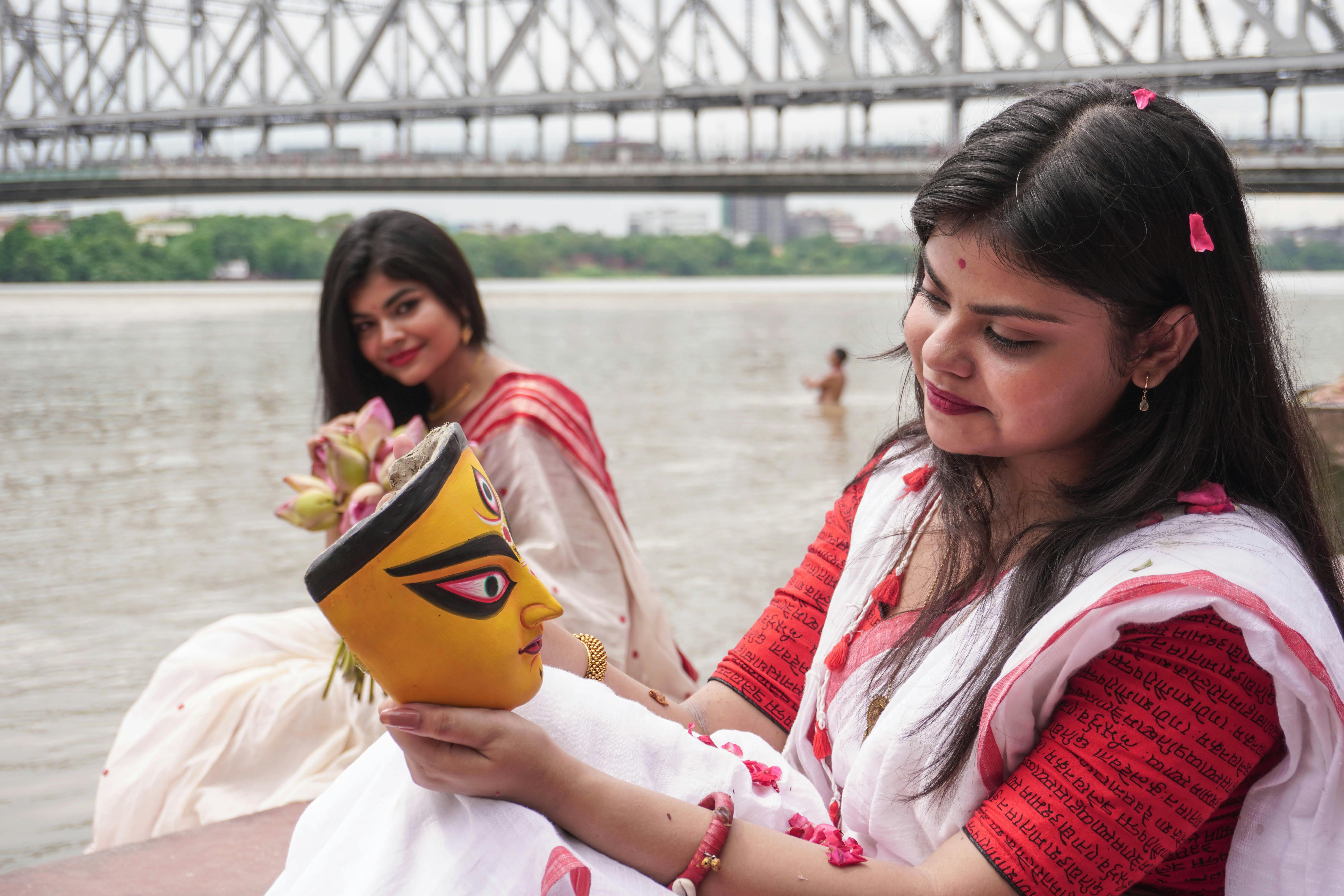 Women in Traditional Clothing Holding Durga Mask · Free Stock Photo