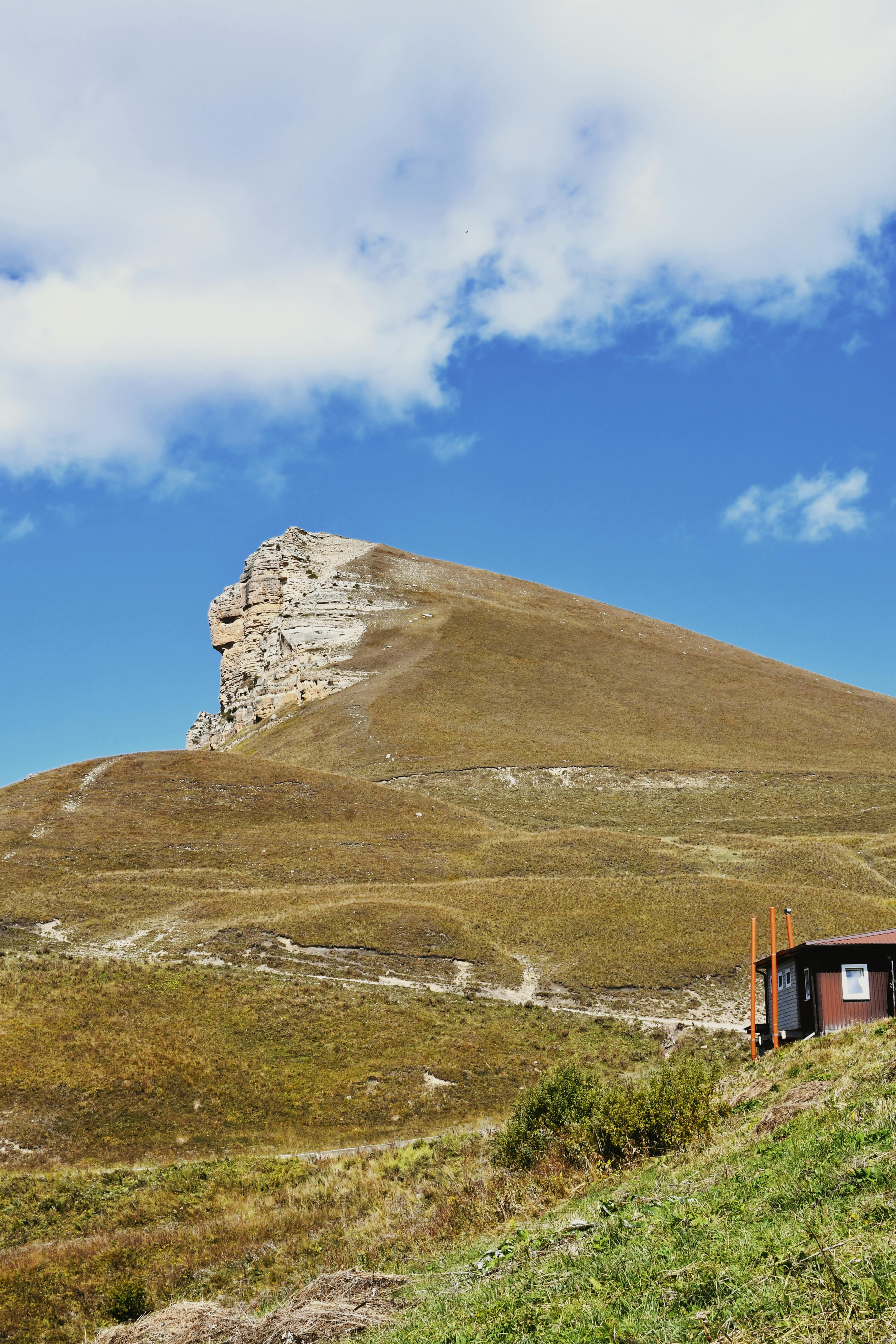 Grassland and Hill with Rock Formation · Free Stock Photo