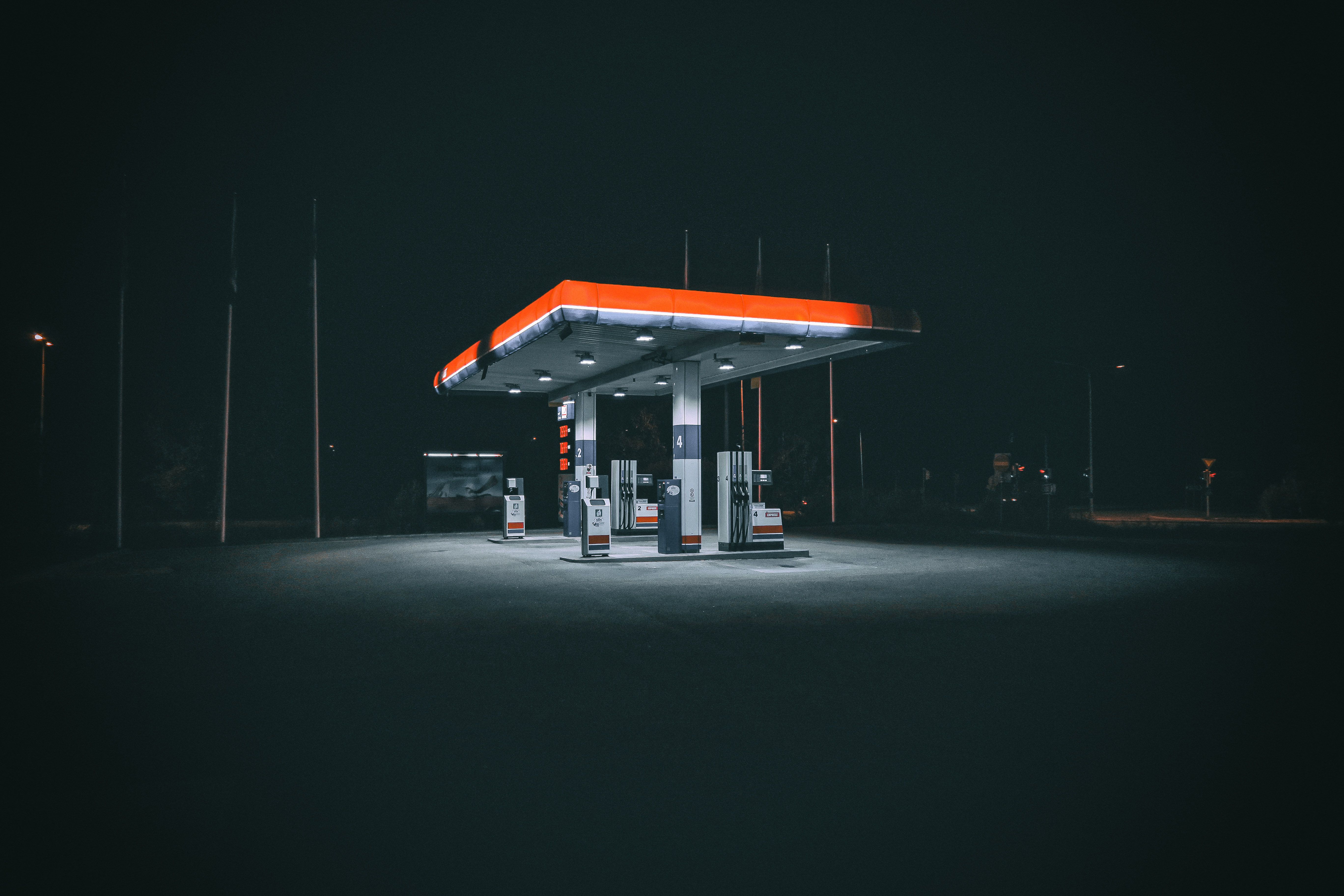 A gas station at night with a red and orange sign · Free Stock Photo