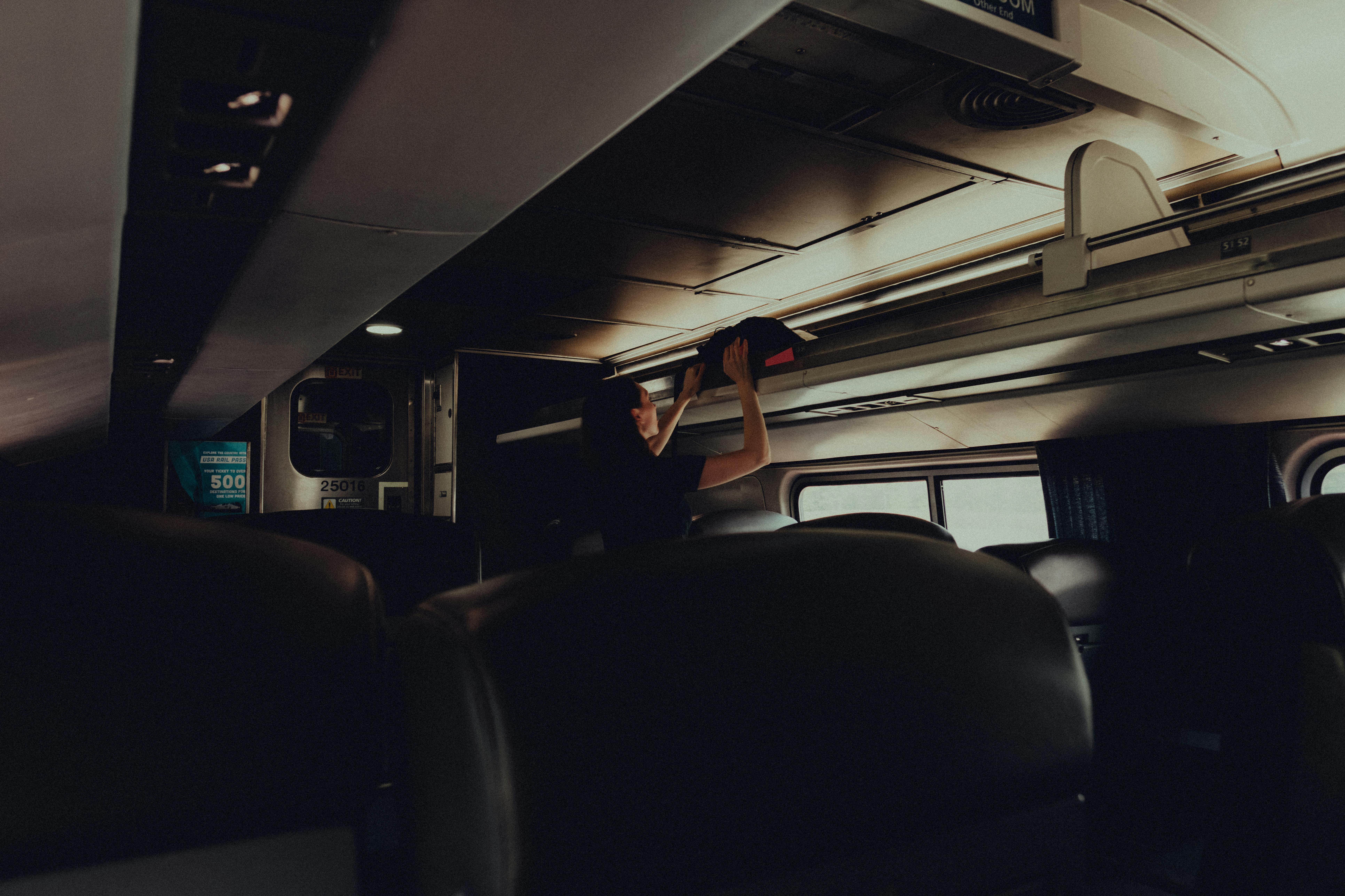 Woman Putting Her Luggage on a Rack in a Modern Train · Free Stock Photo