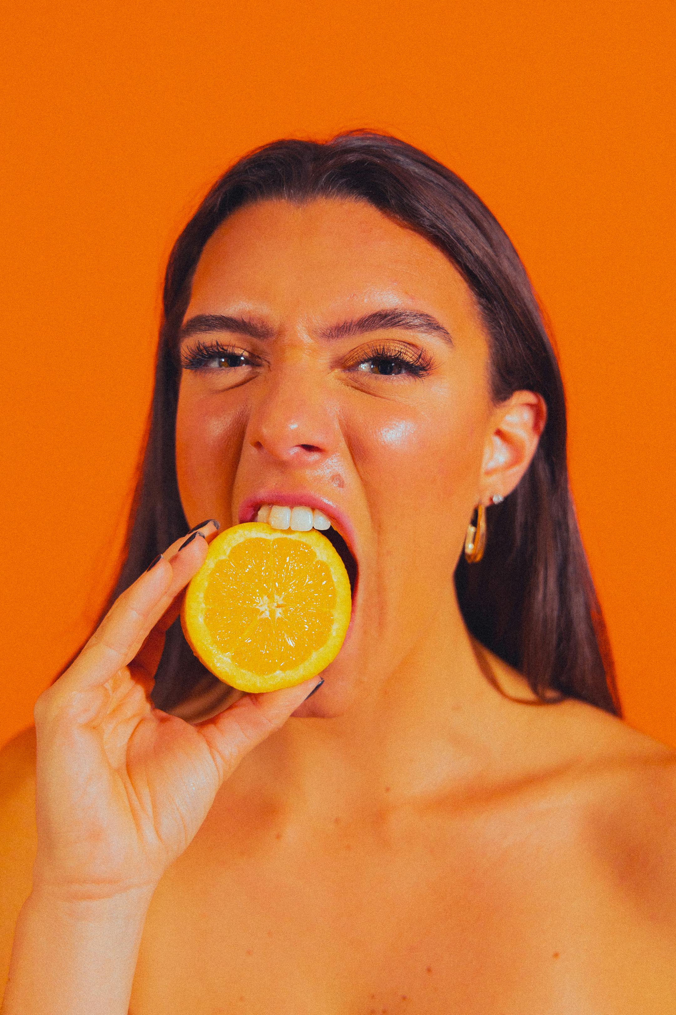 Studio Shot of a Young Woman Biting an Orange · Free Stock Photo