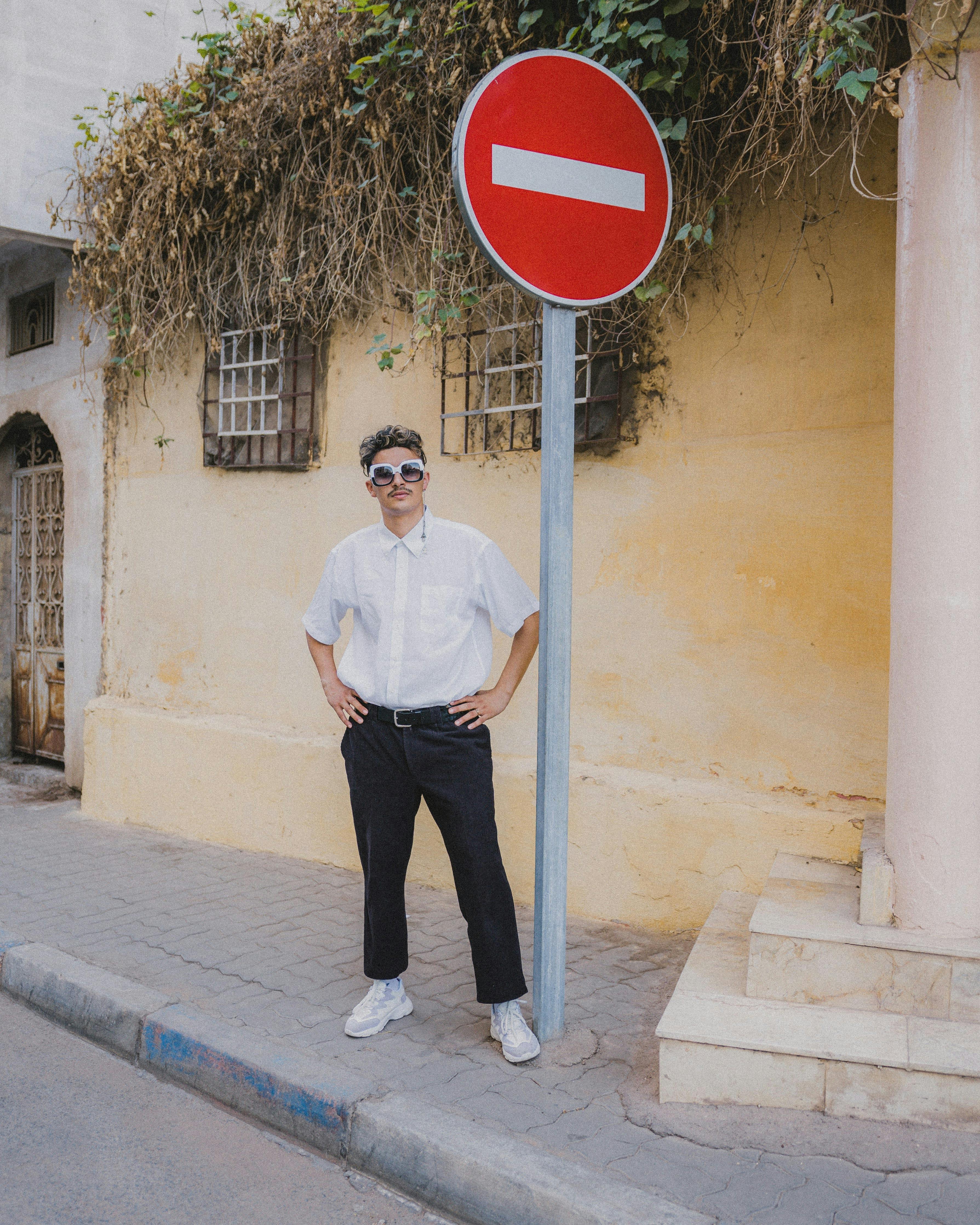 A Man Standing by the Road Sign · Free Stock Photo