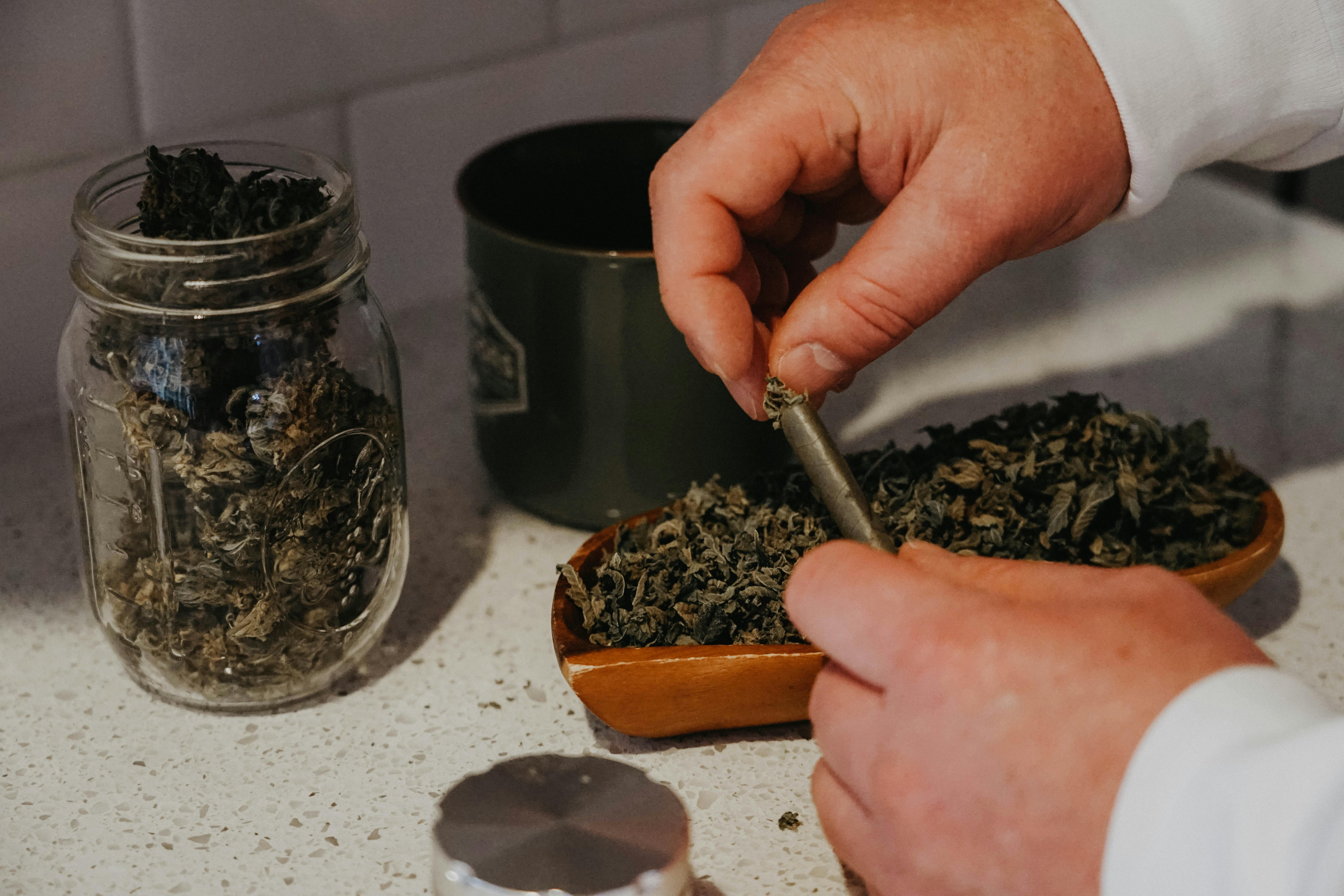 Man Hands over Herbs on Tray and in Jar · Free Stock Photo