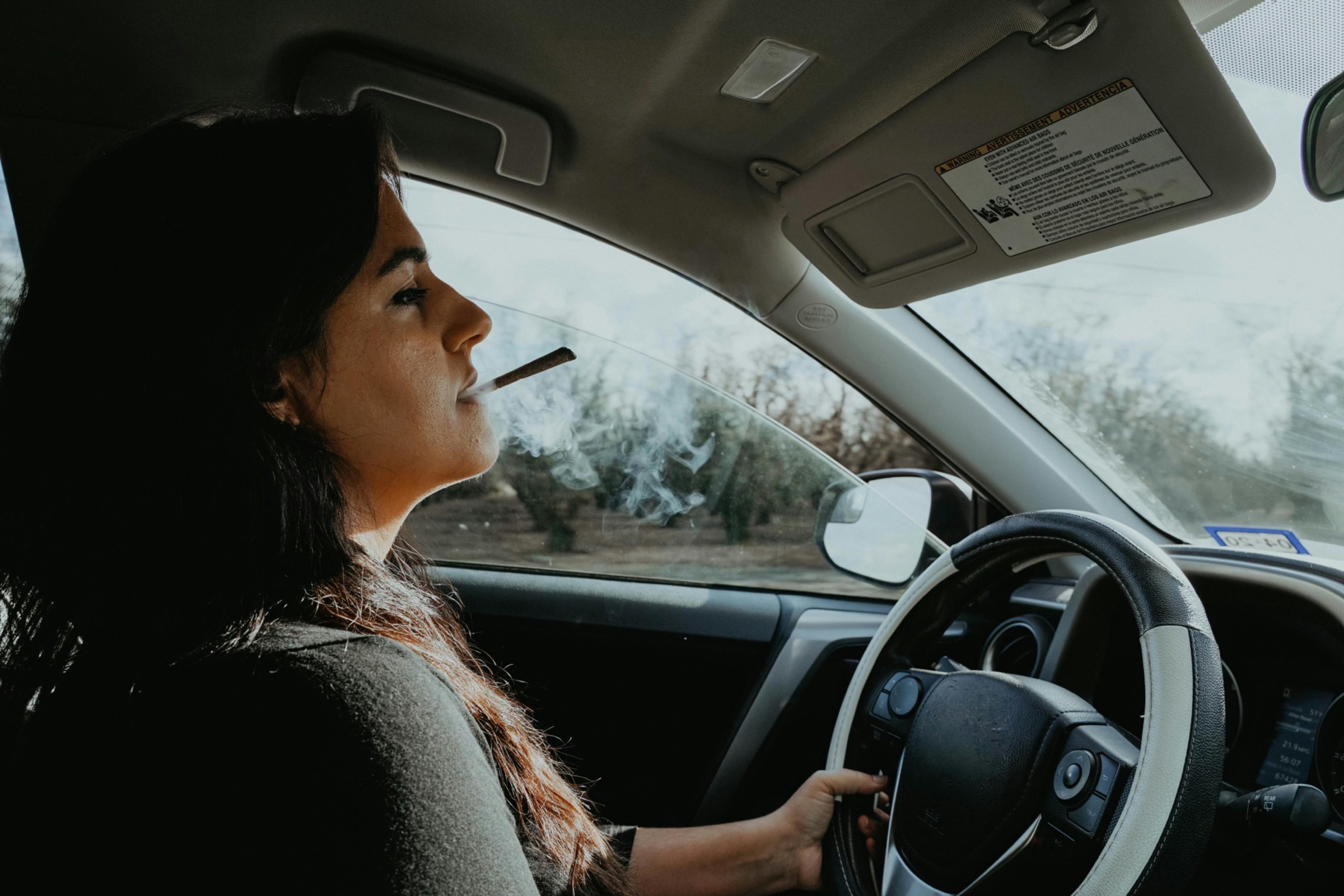 A woman smoking a cigarette while driving a car · Free Stock Photo
