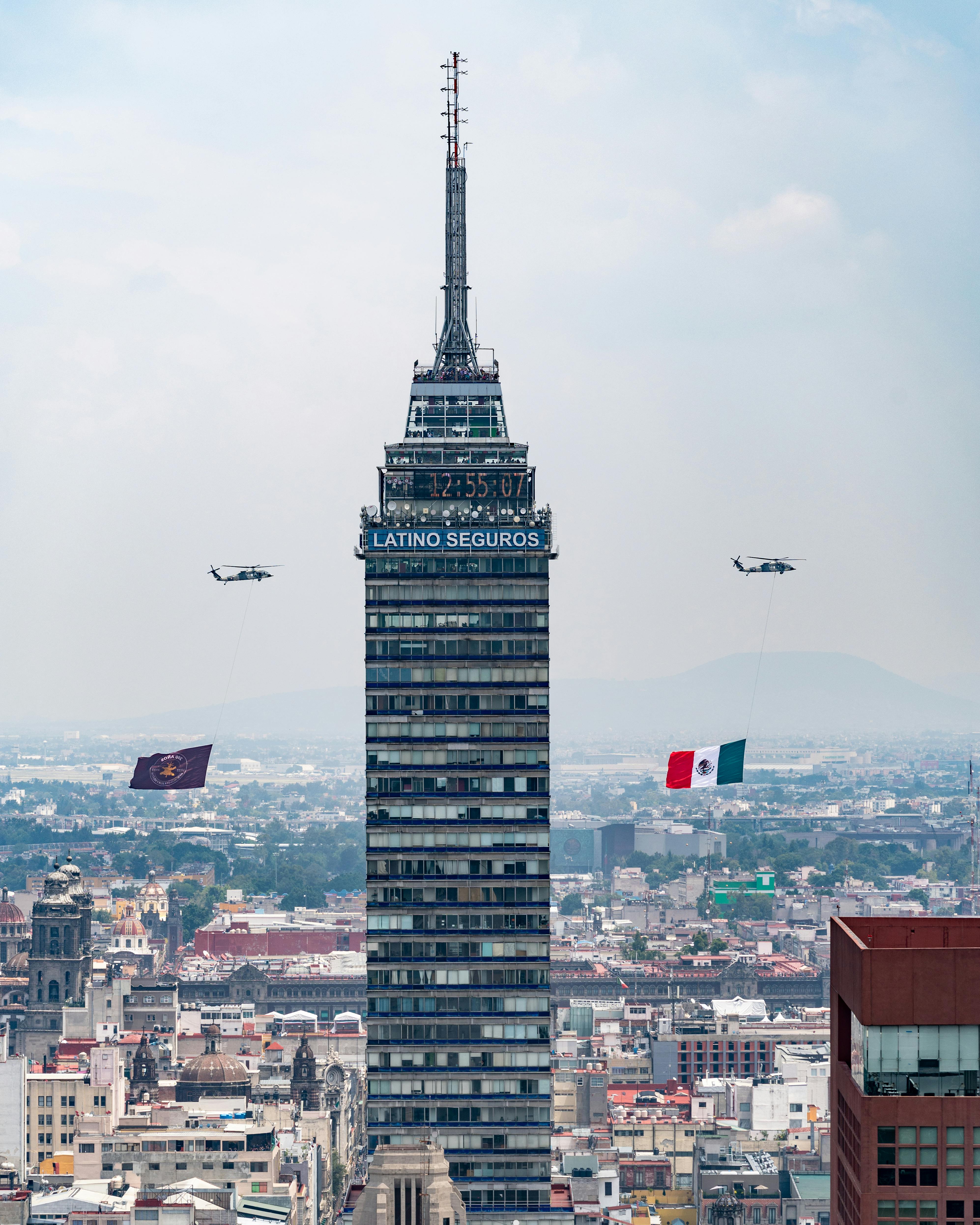 Two planes flying over a city with a tall building in the background ...