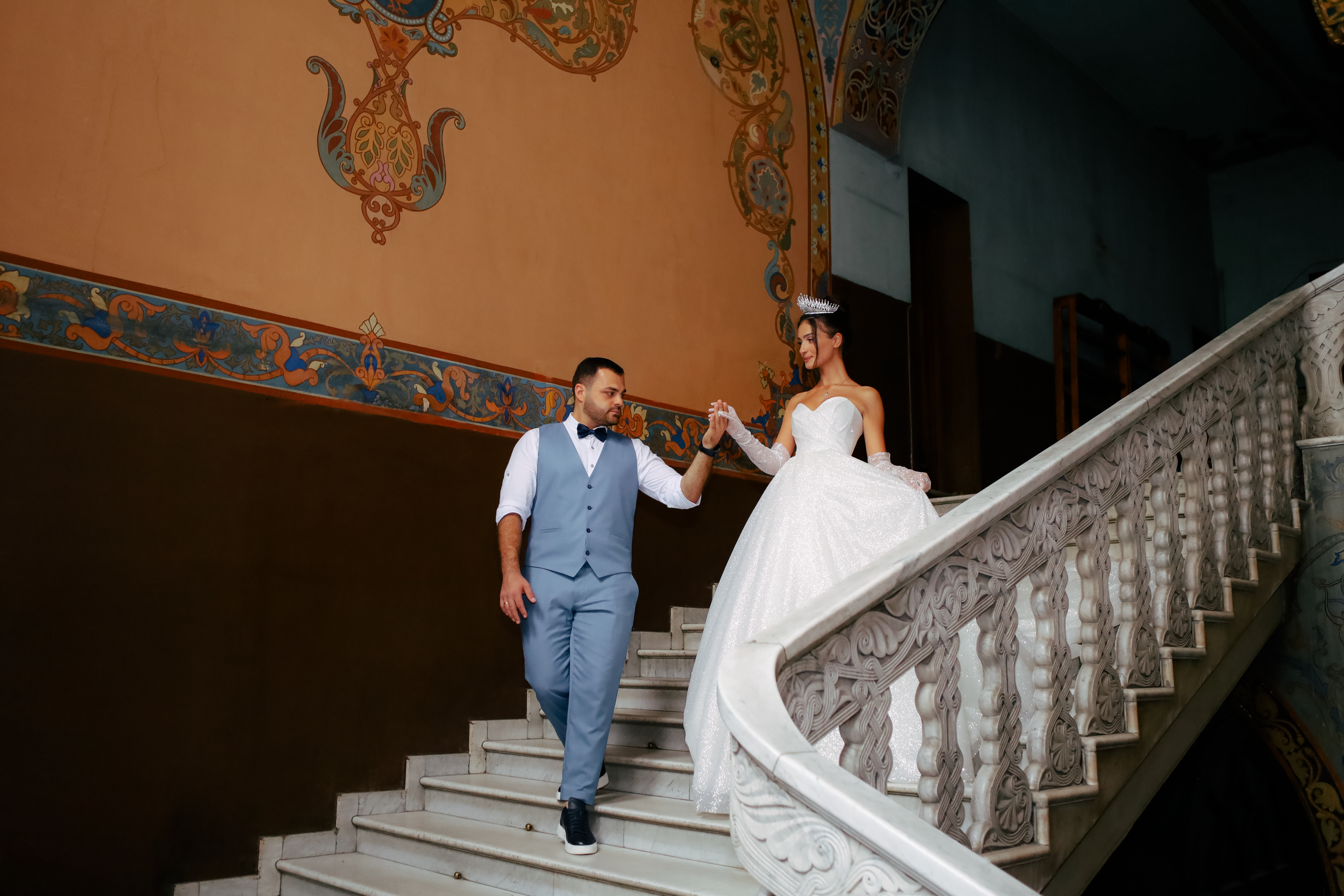 Elegant Groom Leading his Bride Down a Palace Stairway · Free Stock Photo