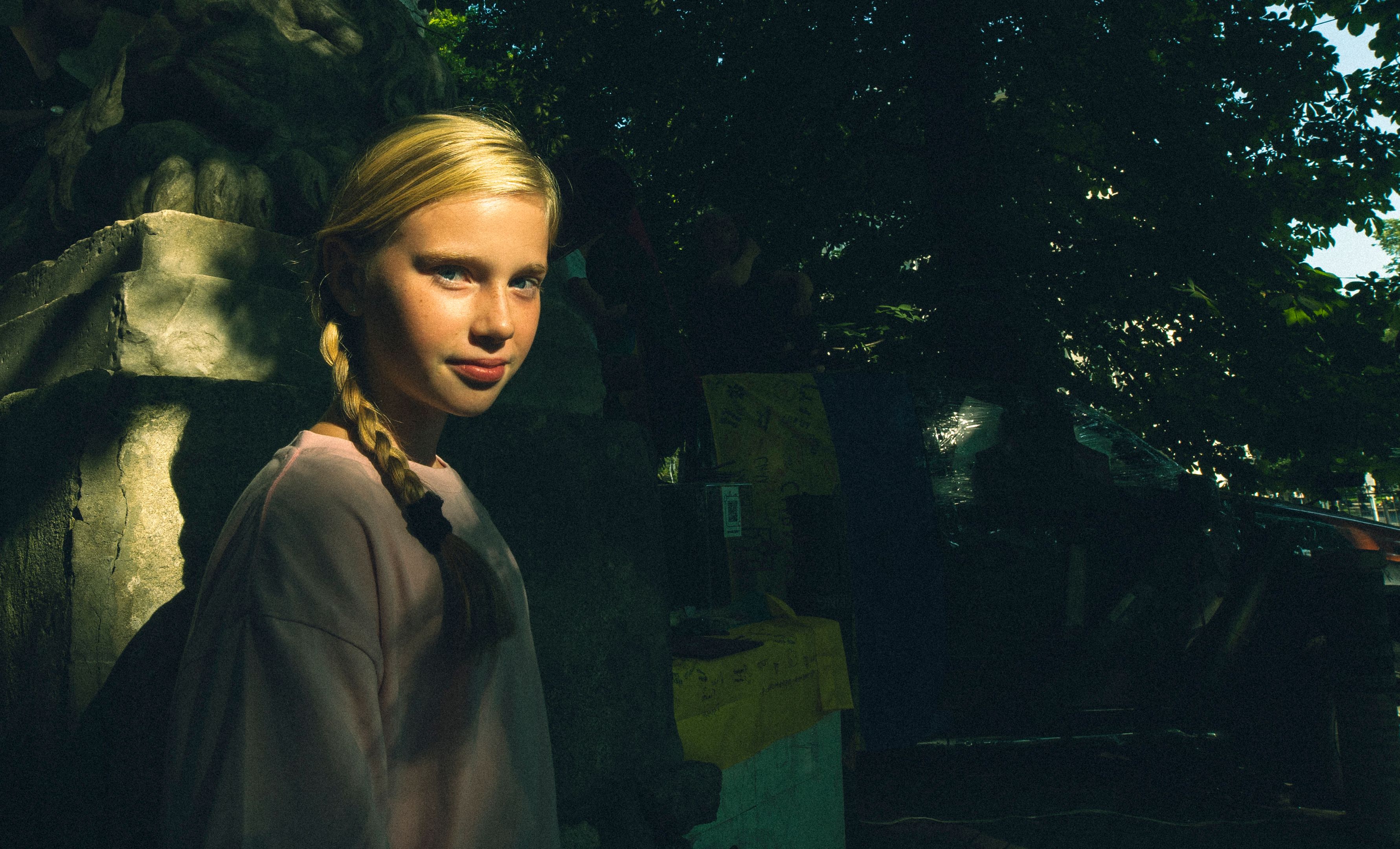 A Girl Standing next to a Statue in a Park with Her Face Illuminated by ...