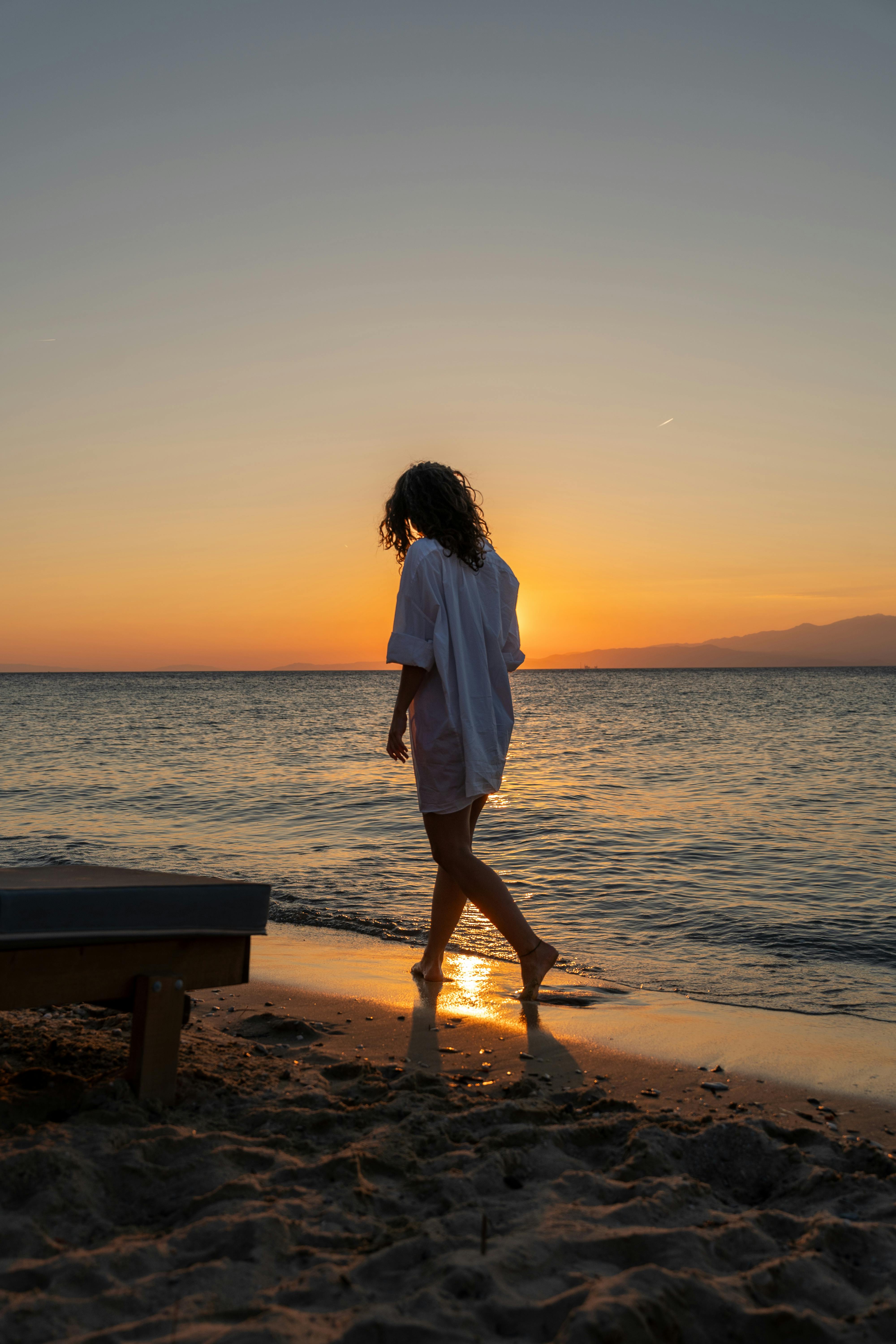 Woman Walking on Sea Shore at Sunset · Free Stock Photo