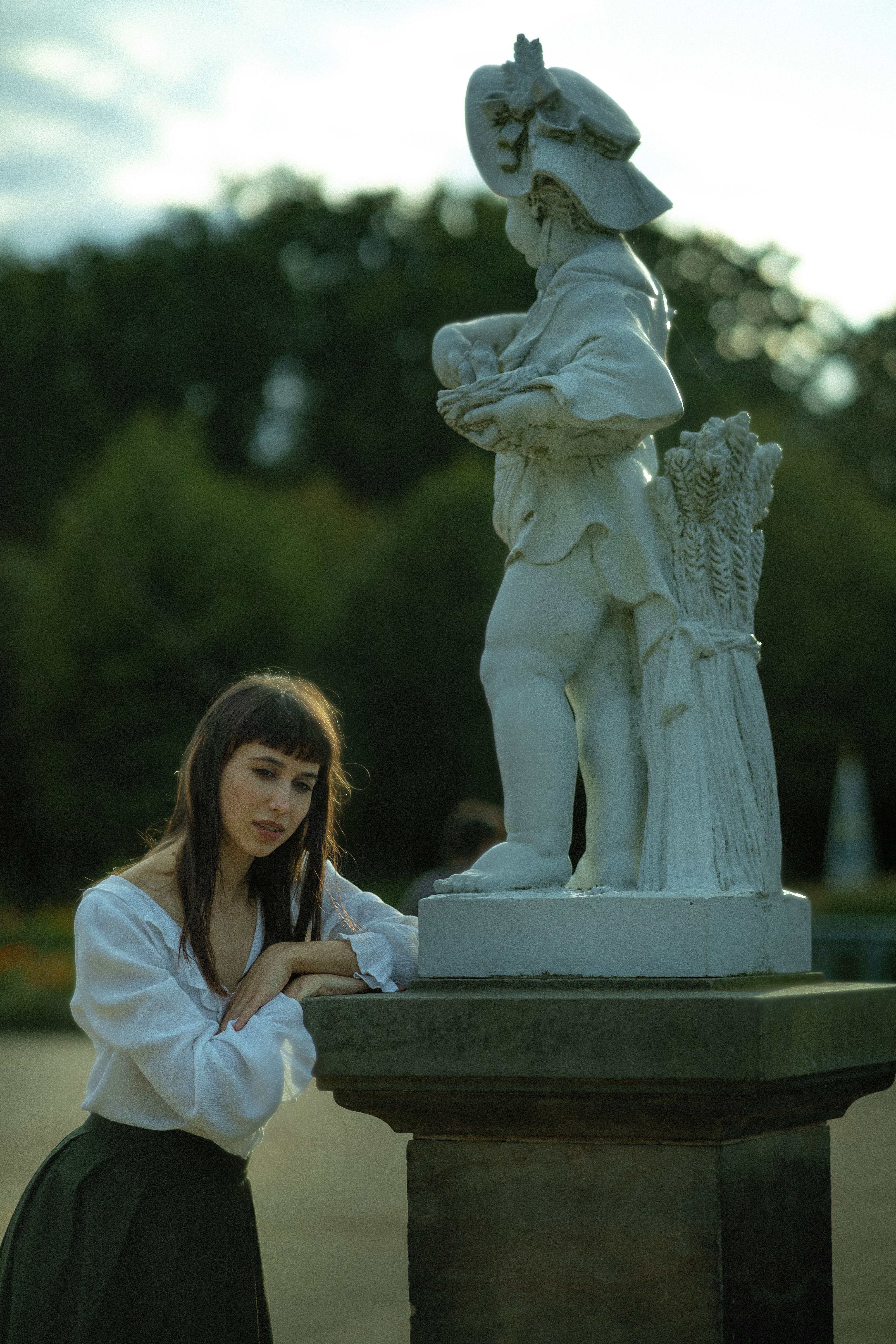 Young Woman Standing next to a Statue in the Park · Free Stock Photo