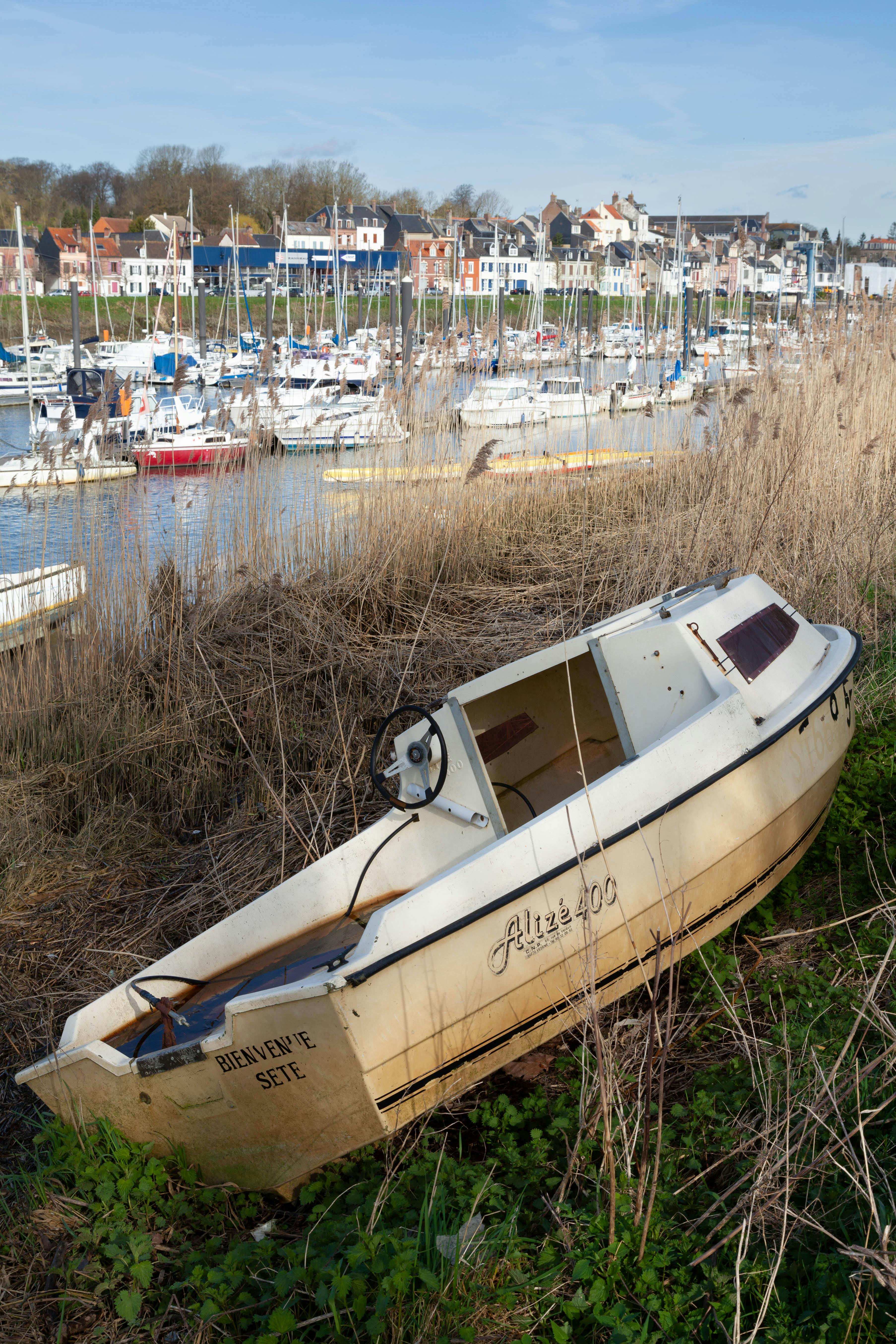 A boat is sitting in the grass near a marina · Free Stock Photo