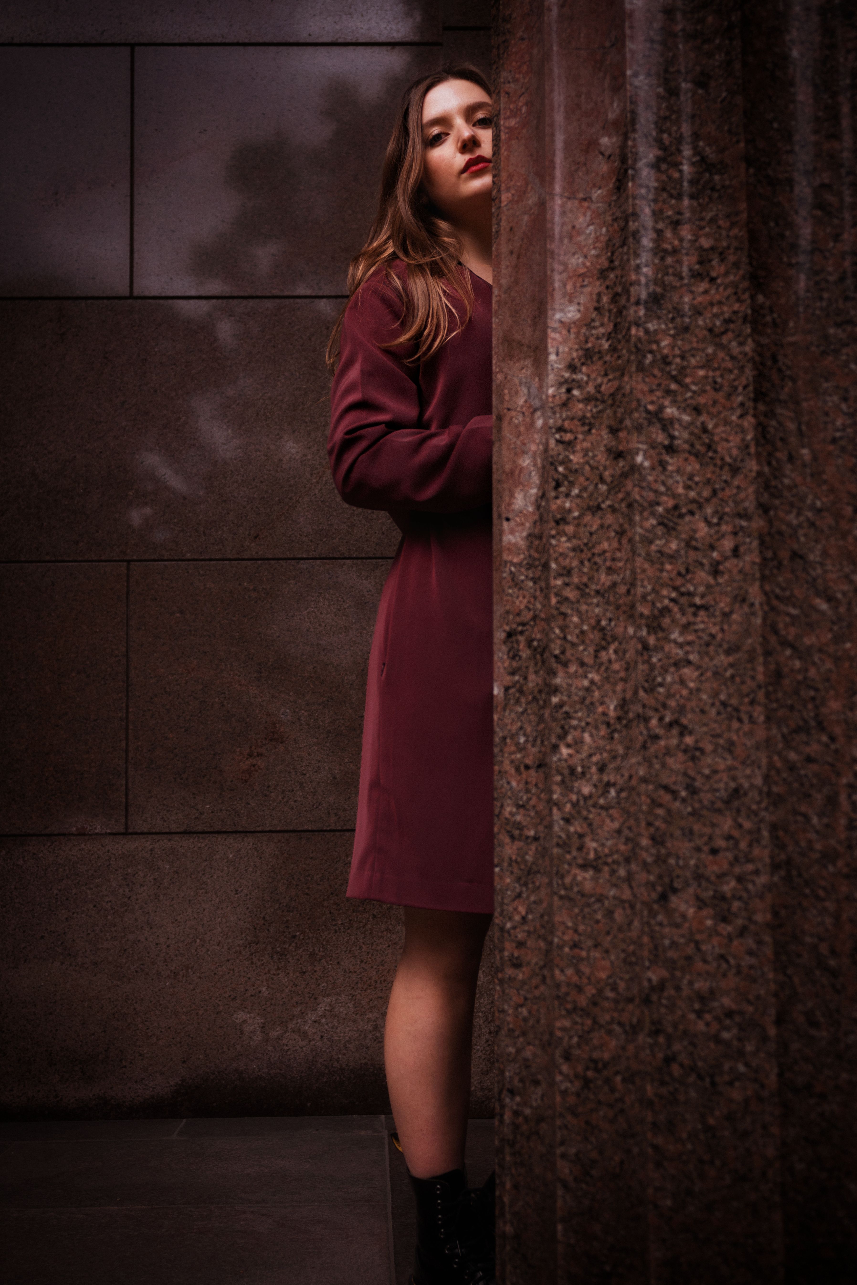Woman in Red Coat Posing behind Wall · Free Stock Photo