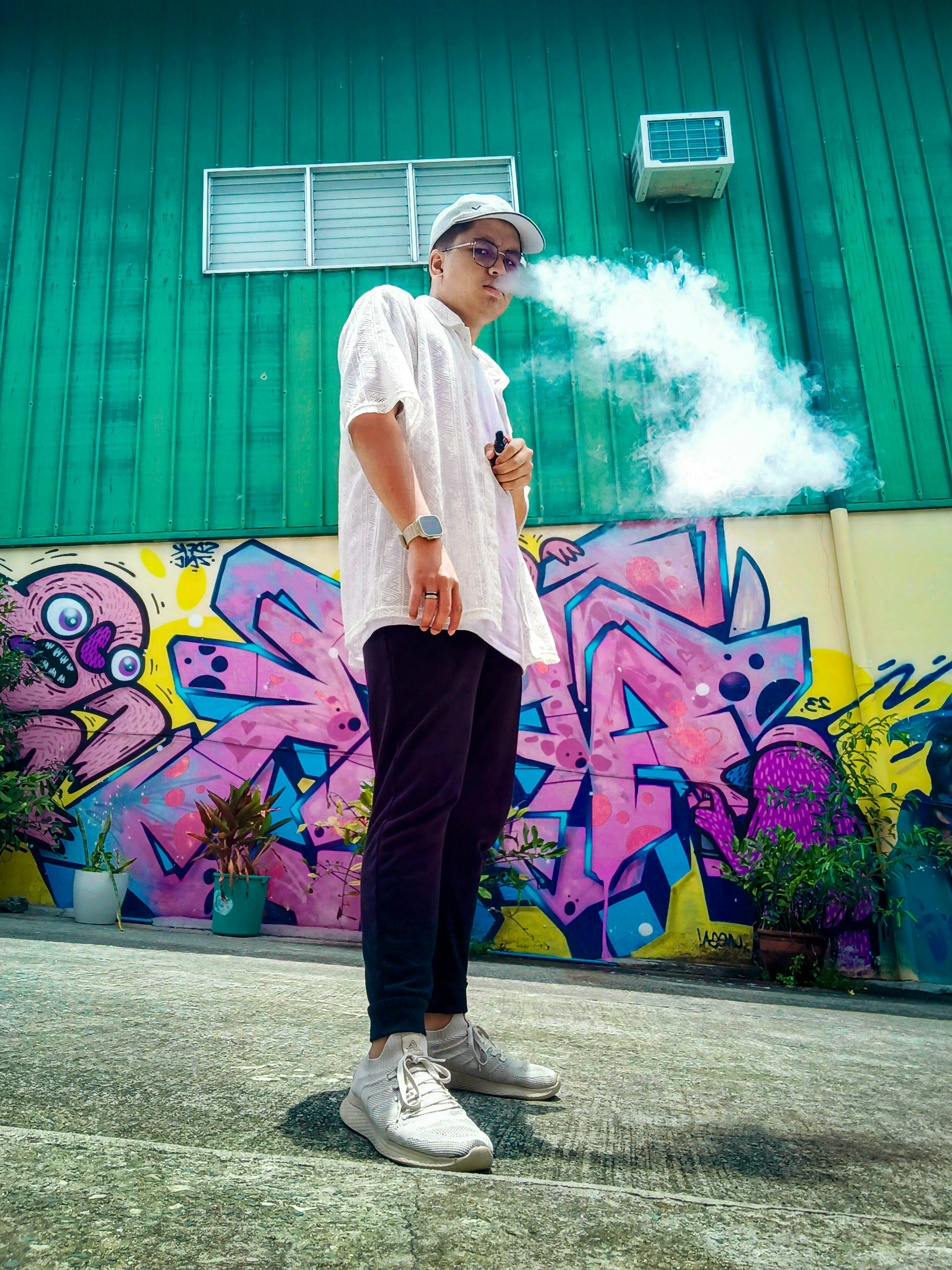 Man Smoking near Wall with Graffiti · Free Stock Photo