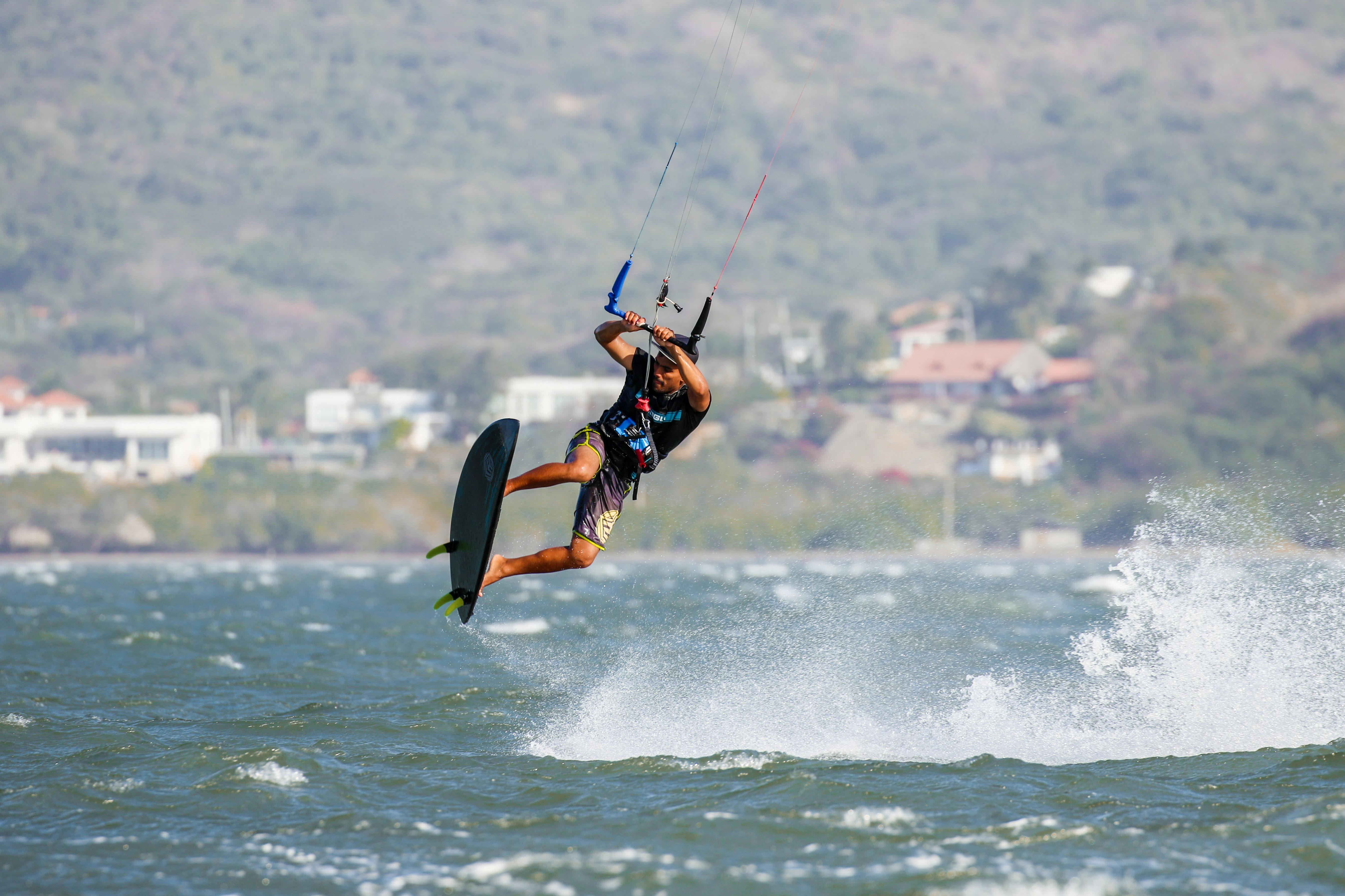 Kiteboarder on a Surfboard With Fins Above the Water · Free Stock Photo