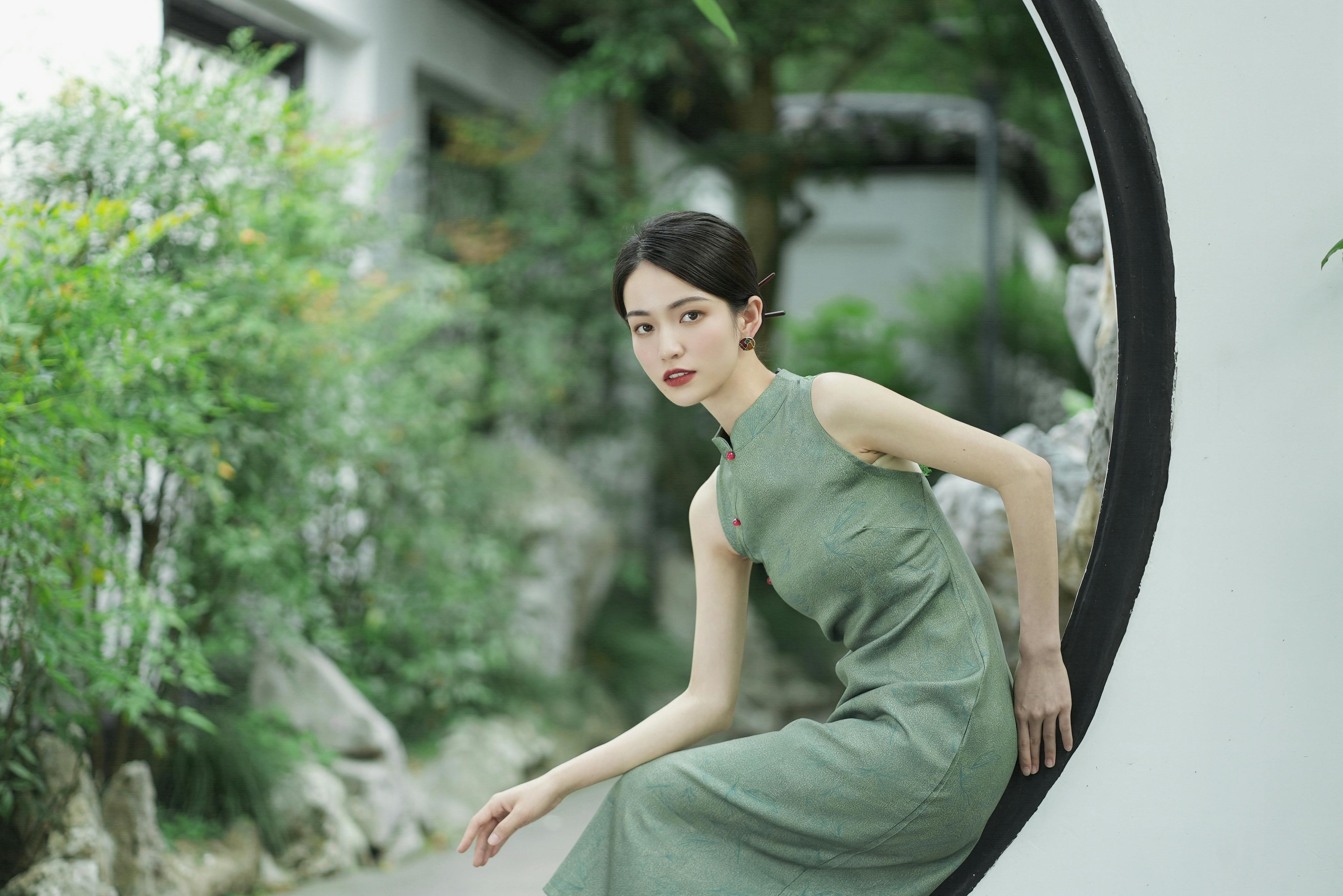 Young Brunette in a White Dress Sitting on a Bench and Holding Flowers ...