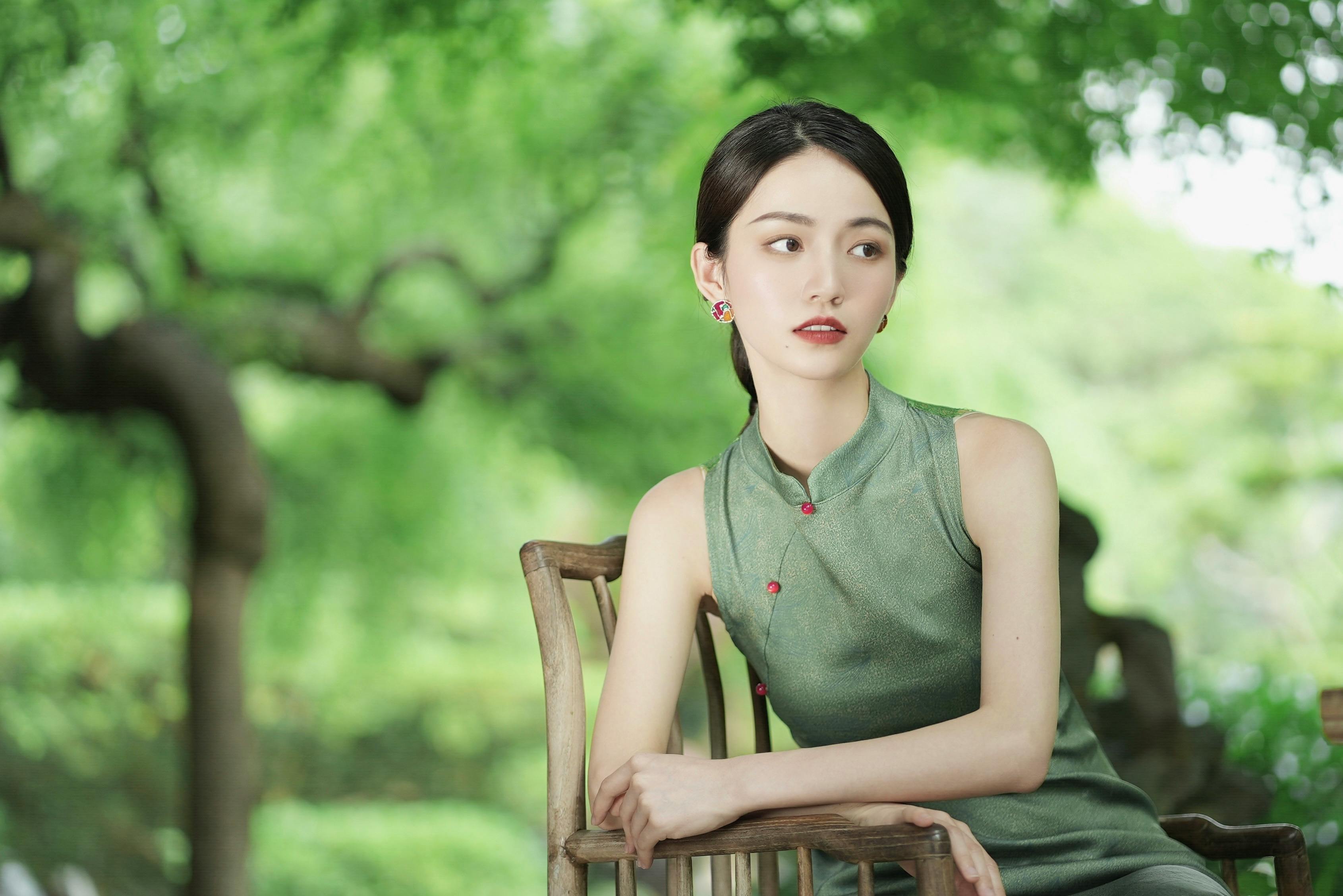 Young Brunette in a White Dress Sitting on a Bench and Holding Flowers ...