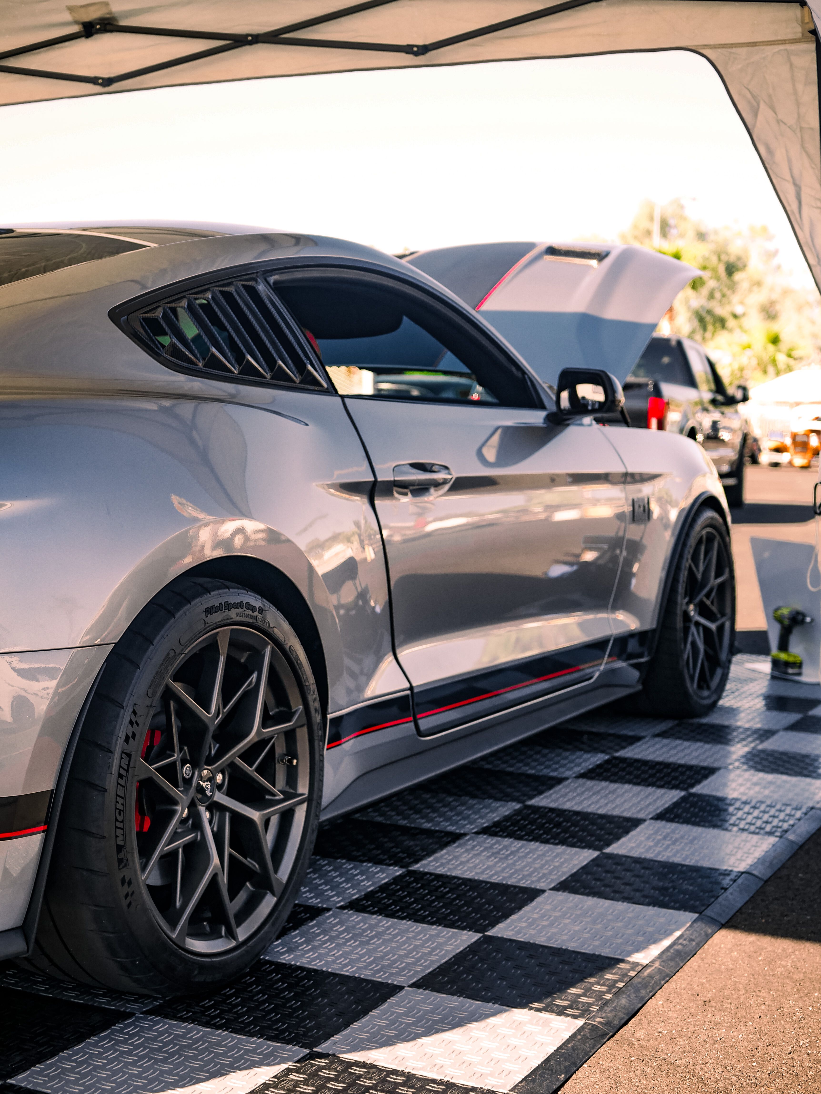 The rear end of a mustang car parked on a checkered floor · Free Stock ...