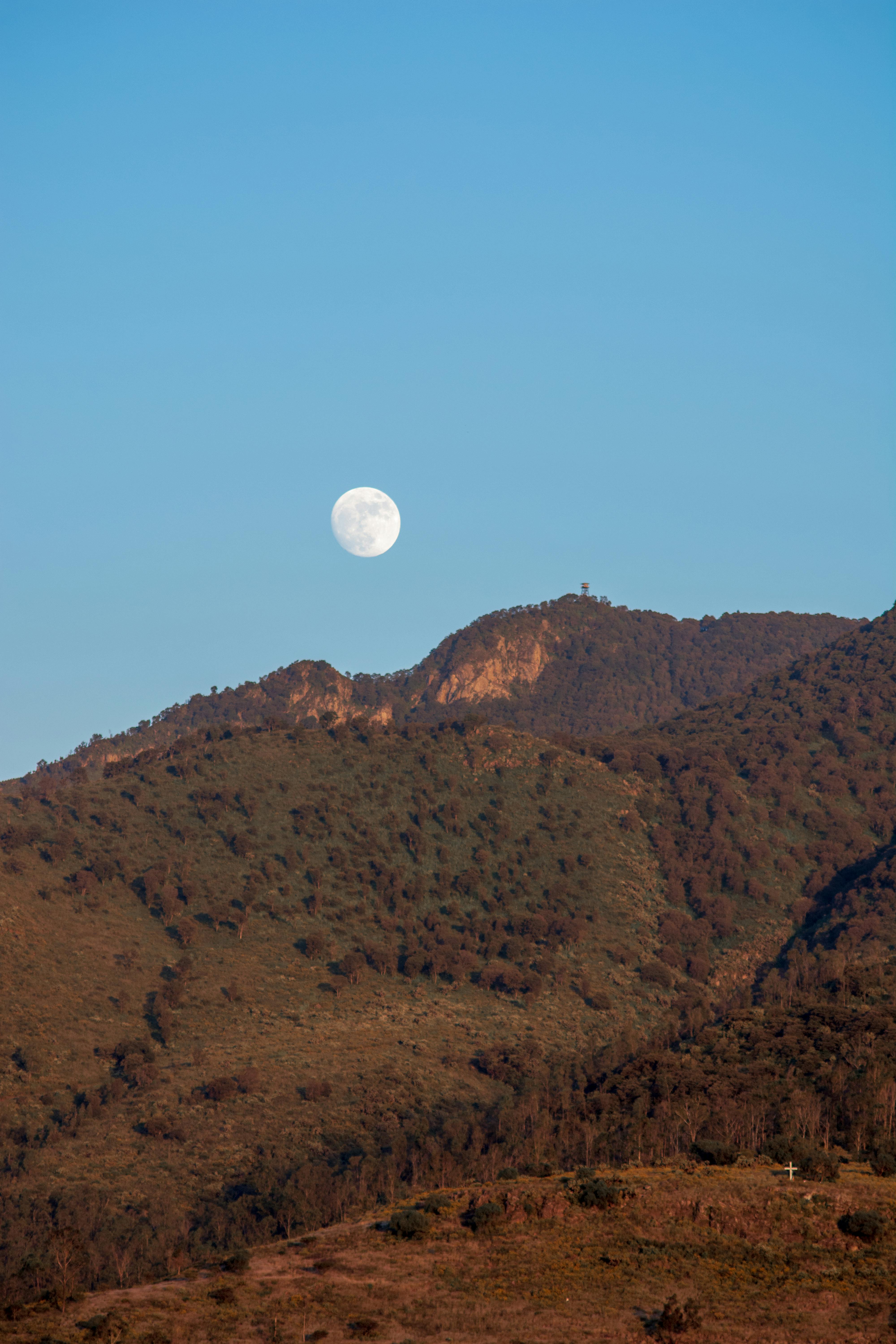 A full moon rises over the mountains in the distance · Free Stock Photo