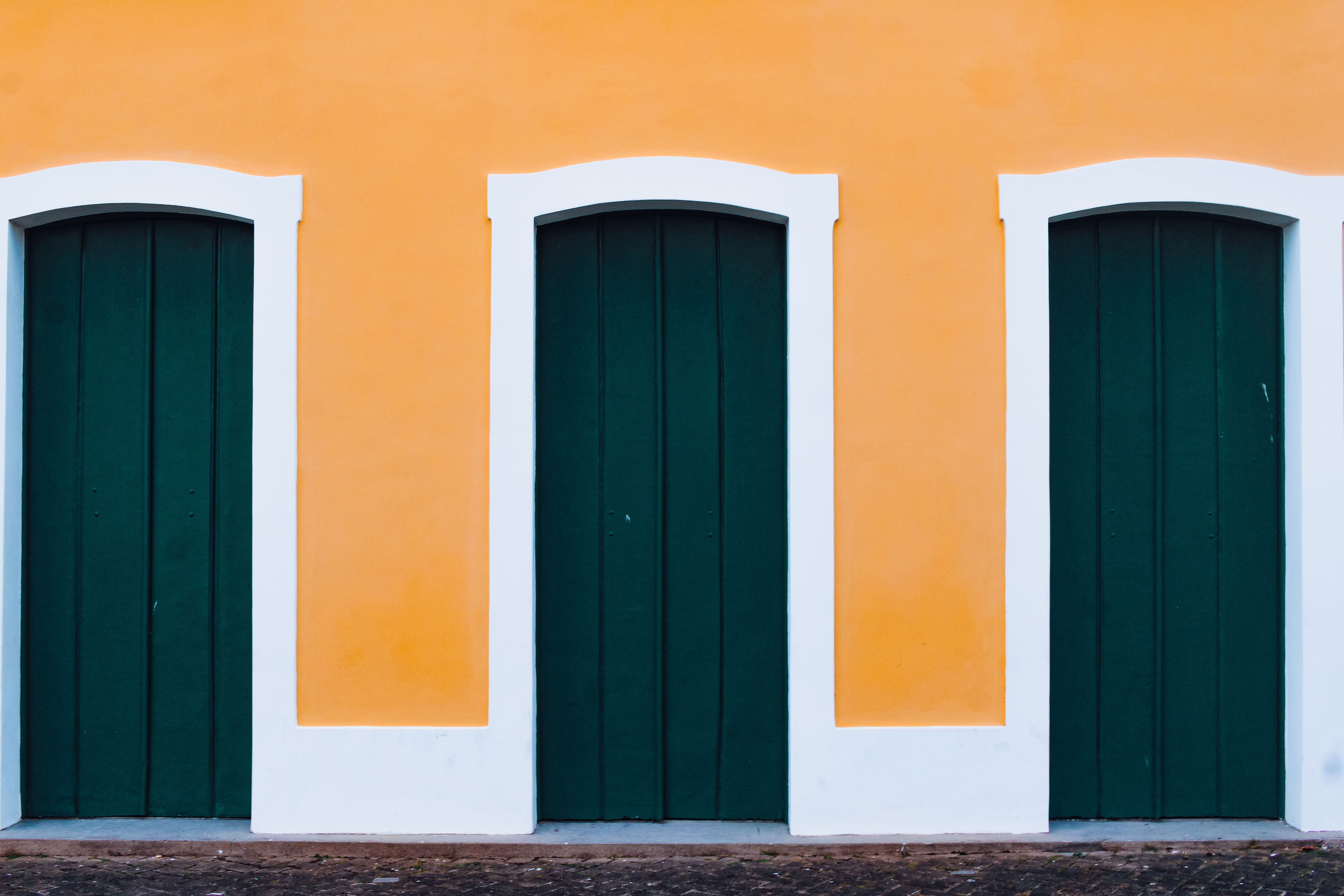 Three green doors on a yellow wall · Free Stock Photo