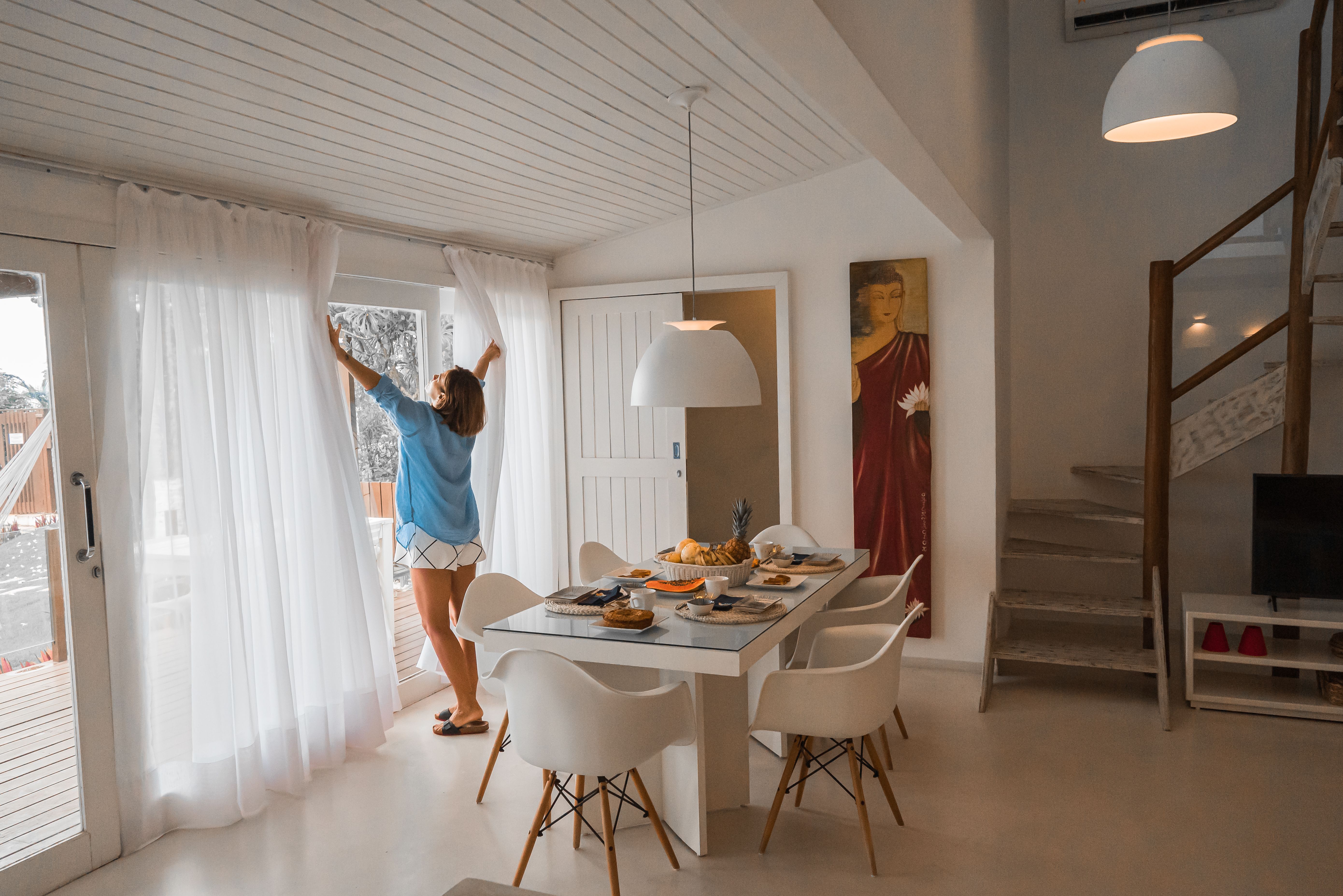 A woman standing in front of a white dining room table · Free Stock Photo