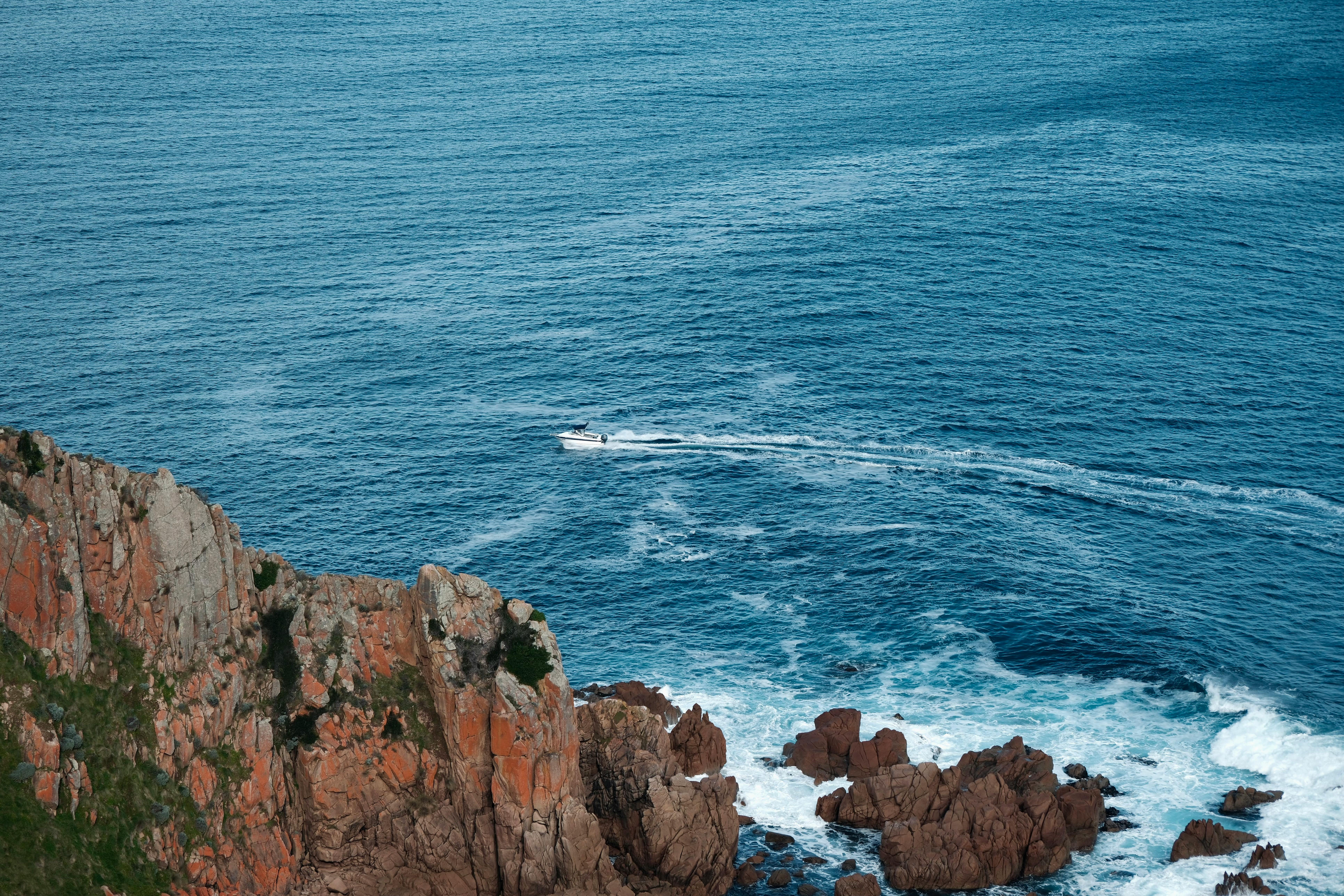 Motorboat behind Rocks on Sea Shore · Free Stock Photo