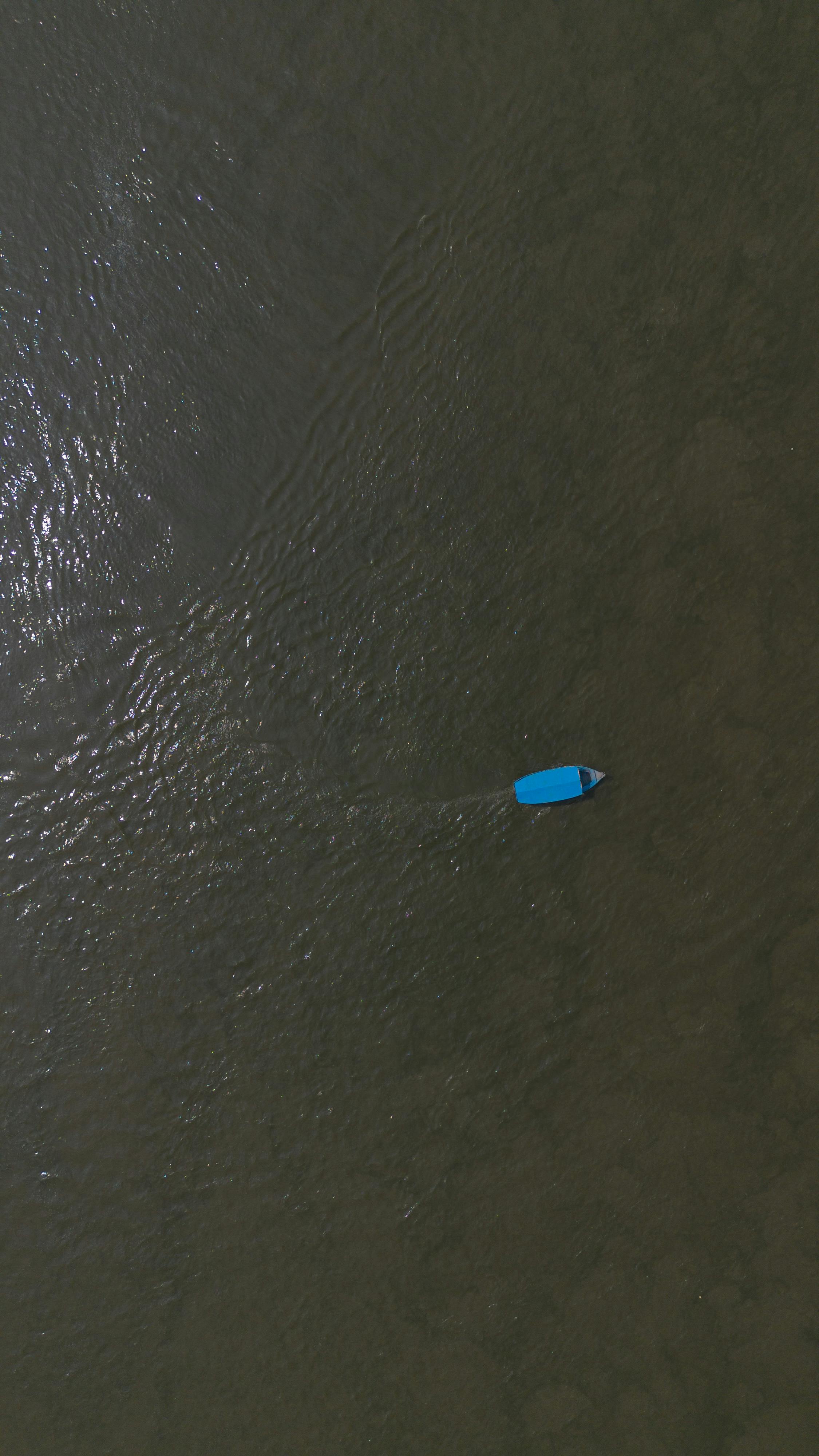 An aerial view of a small boat floating in the water · Free Stock Photo