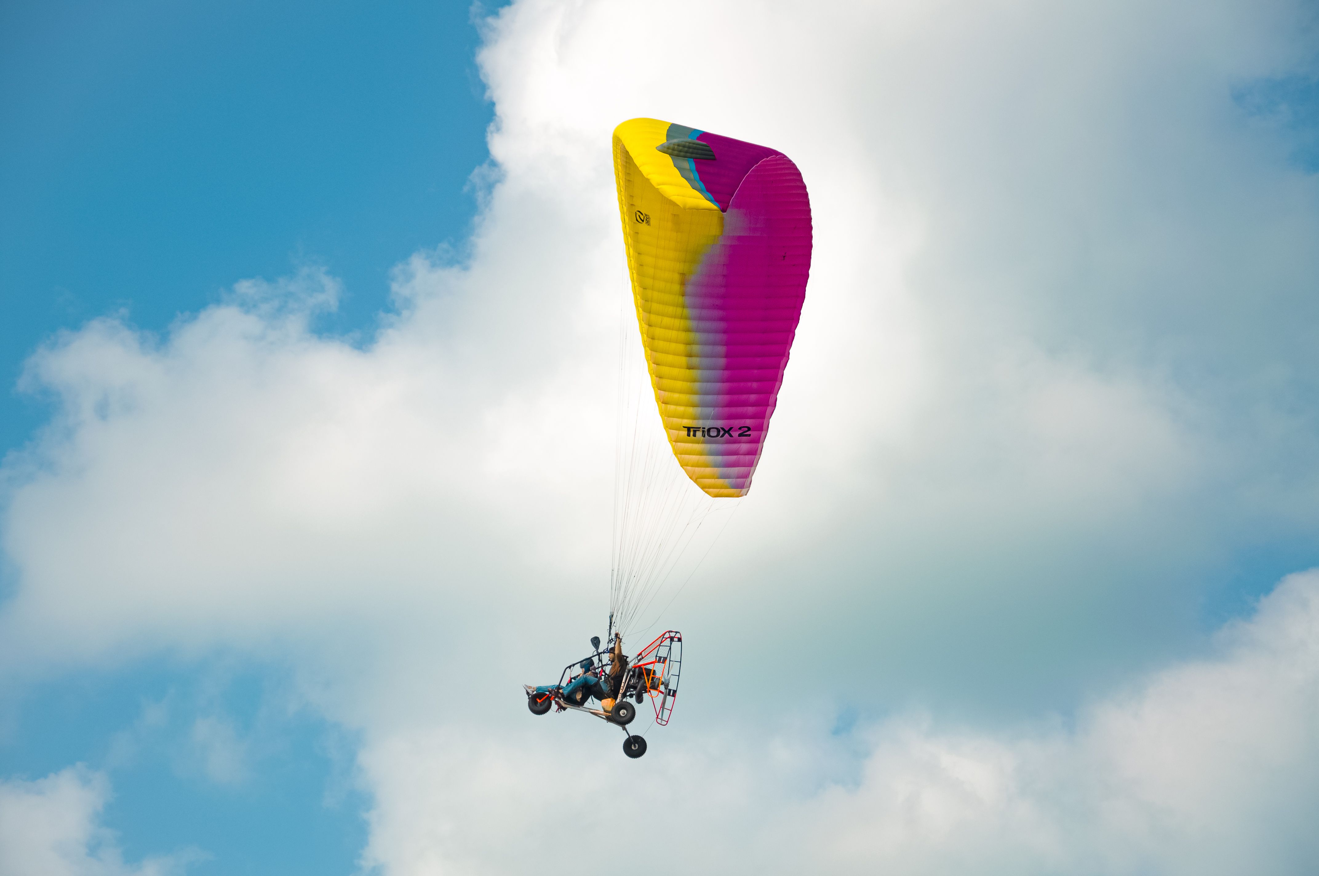 A paraglider is flying through the sky with a colorful parachute · Free ...