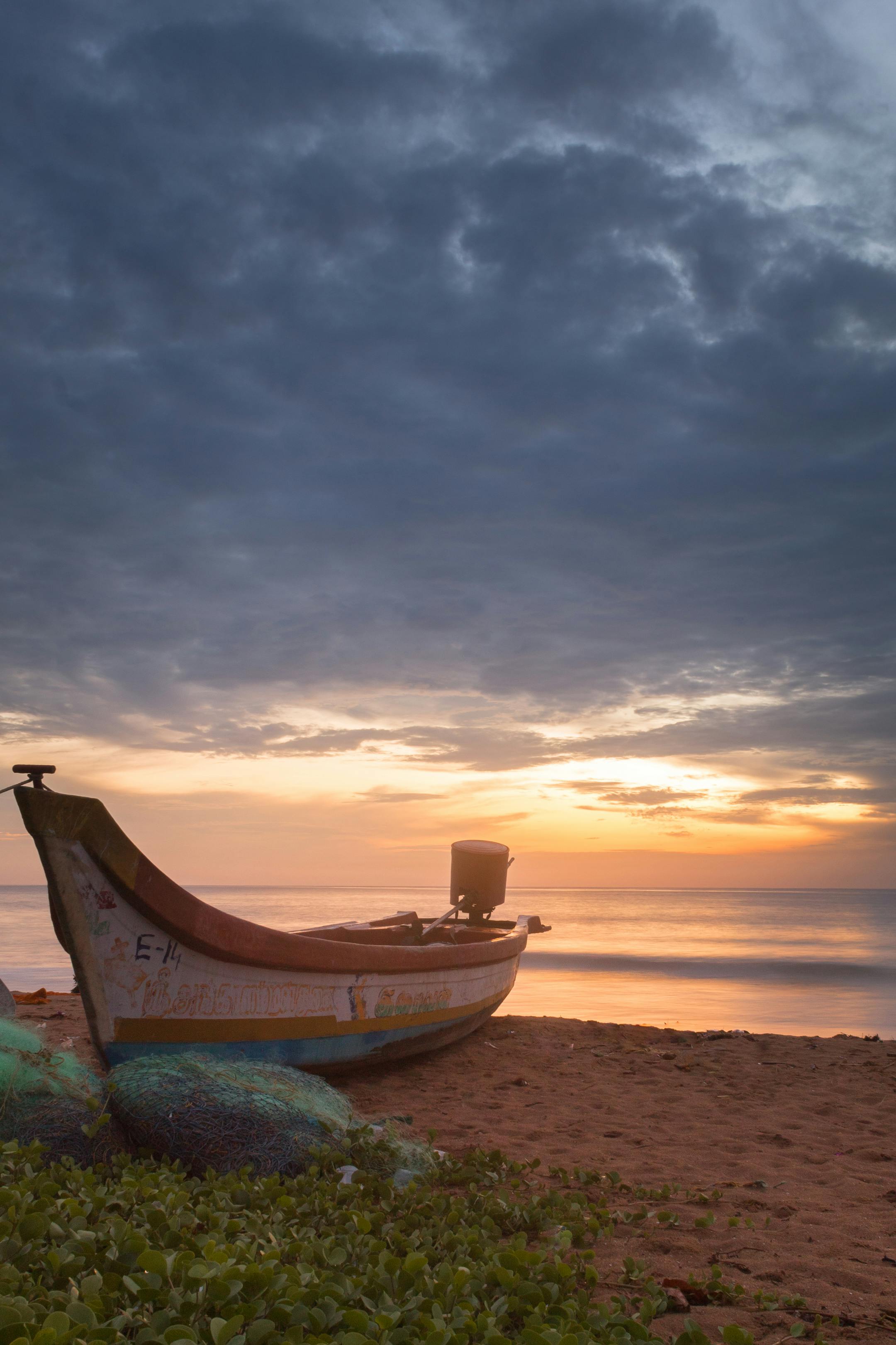 Rain Cloud over Empty Motorboat on Beach at Sunset · Free Stock Photo