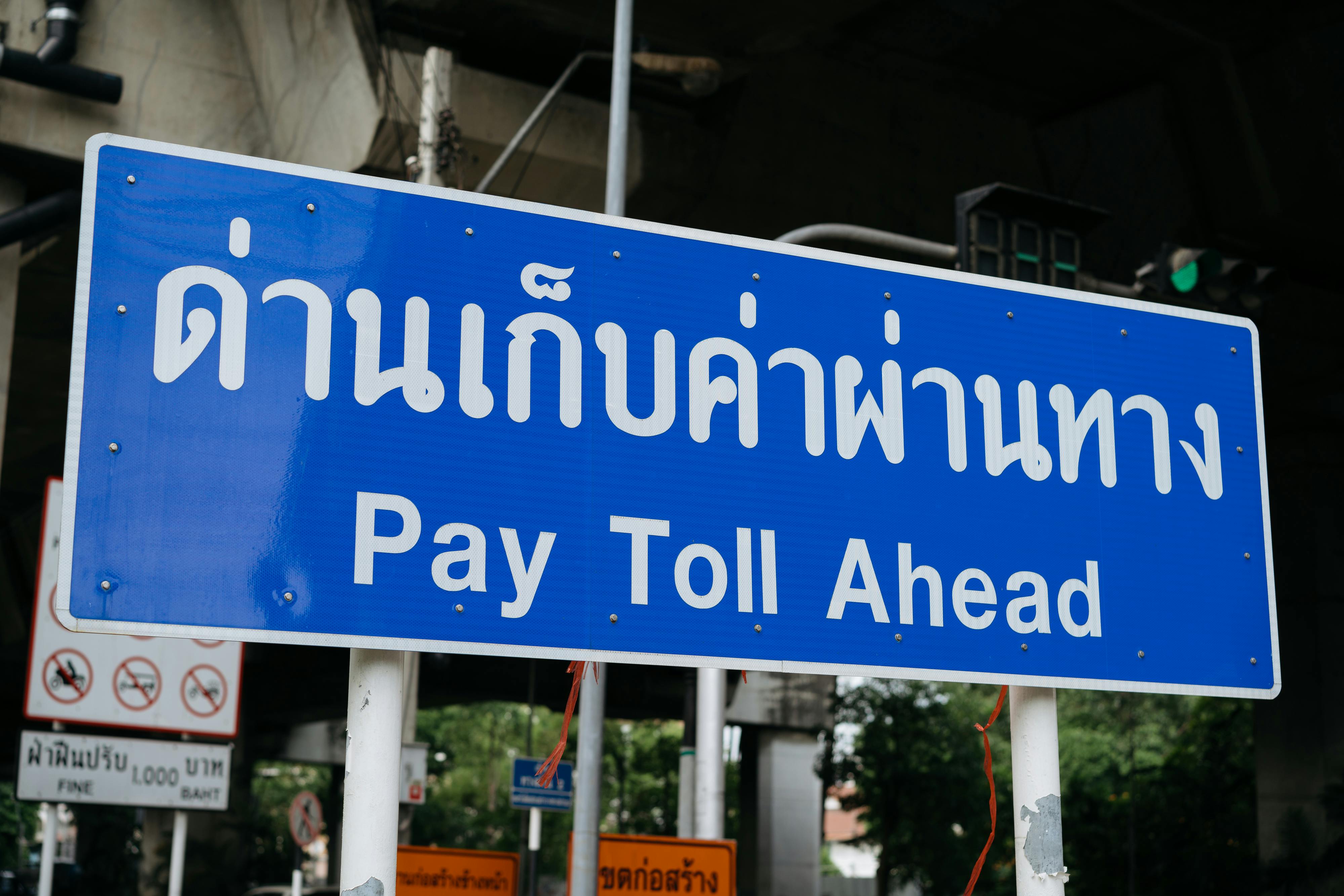 A sign that says pay toll ahead in thai · Free Stock Photo