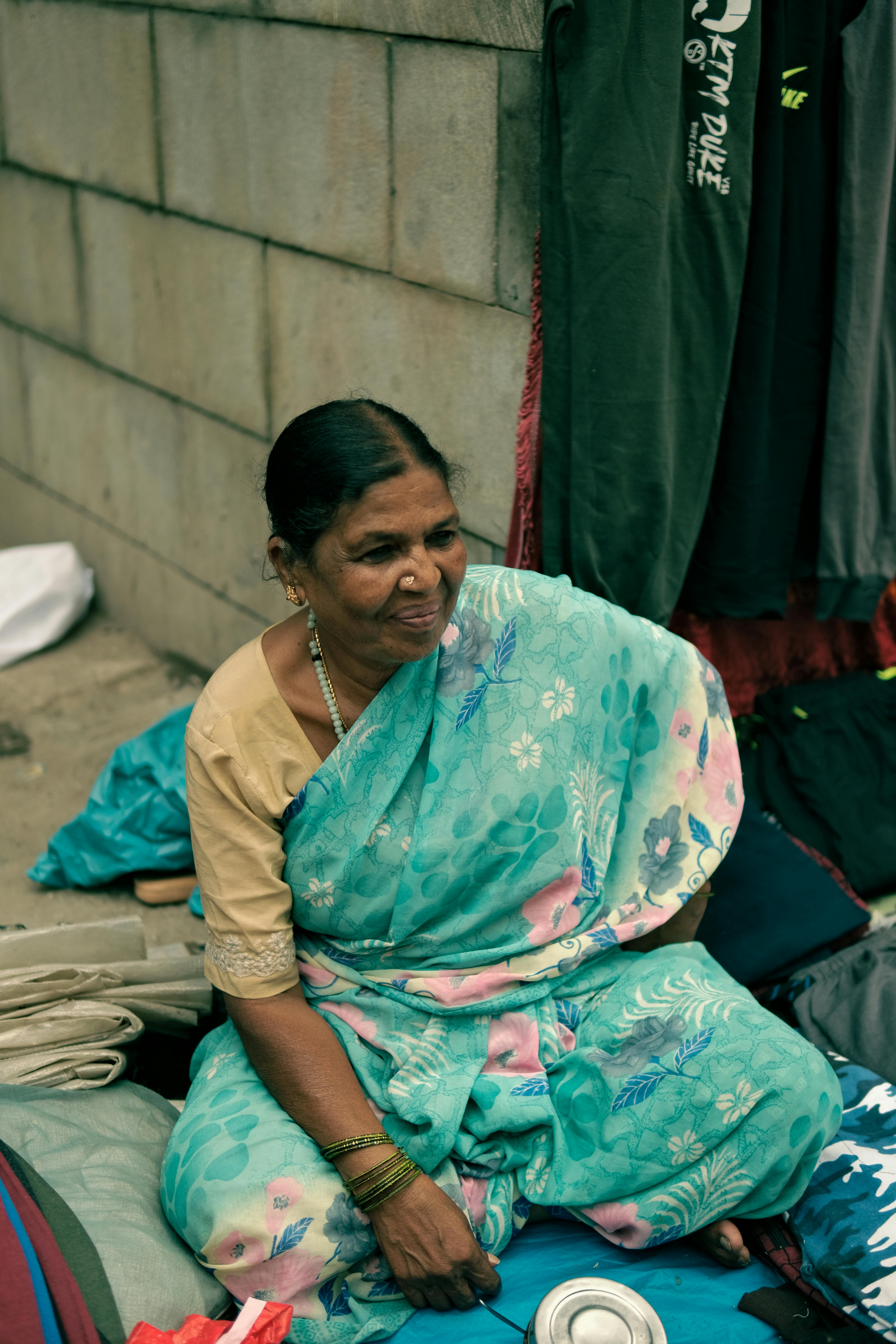A woman sitting on the ground in front of a pile of clothes · Free ...