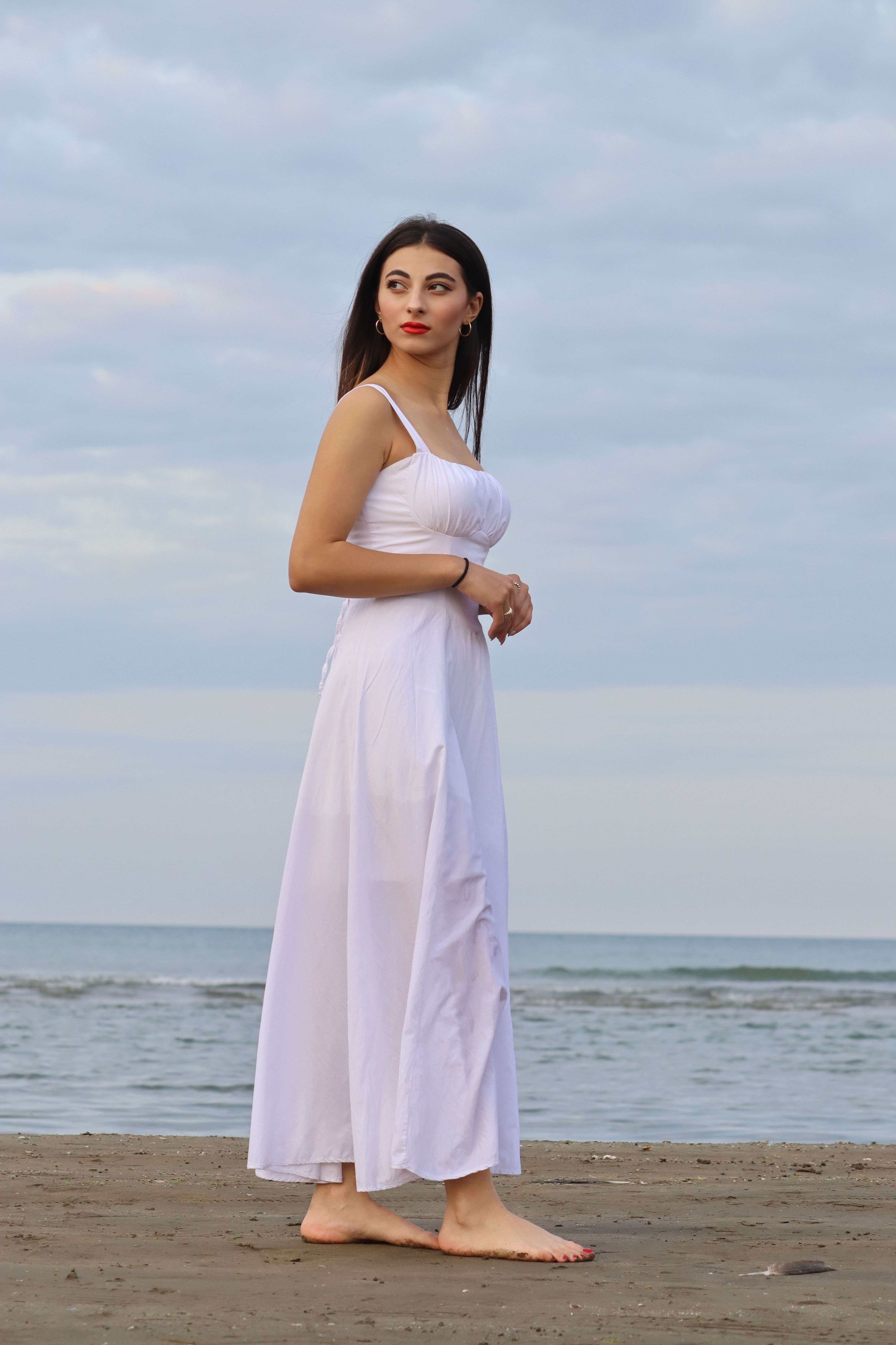 Model Wearing a White Sundress Standing on One Leg Among Cattails ...
