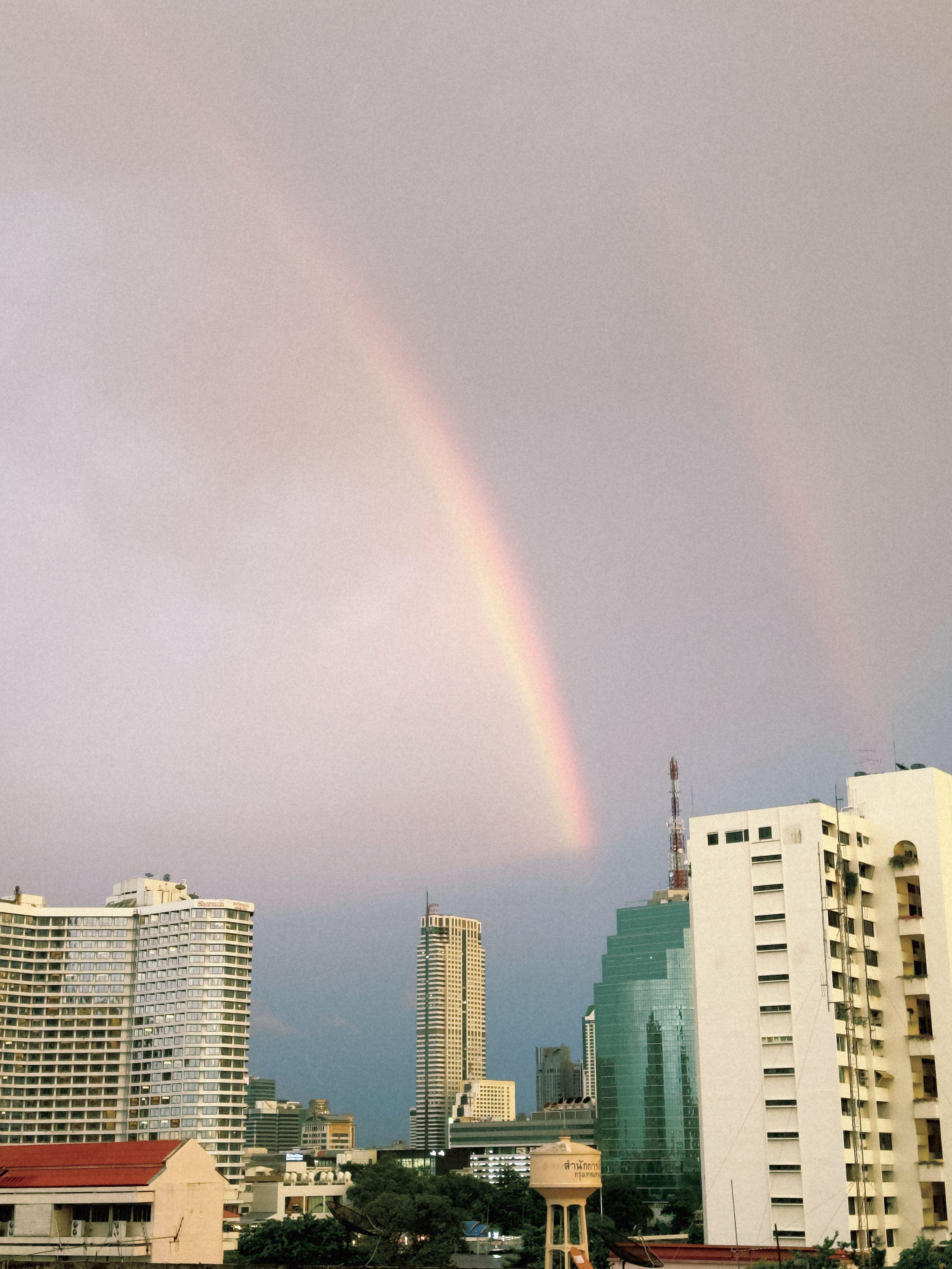 A rainbow is seen over a city skyline · Free Stock Photo