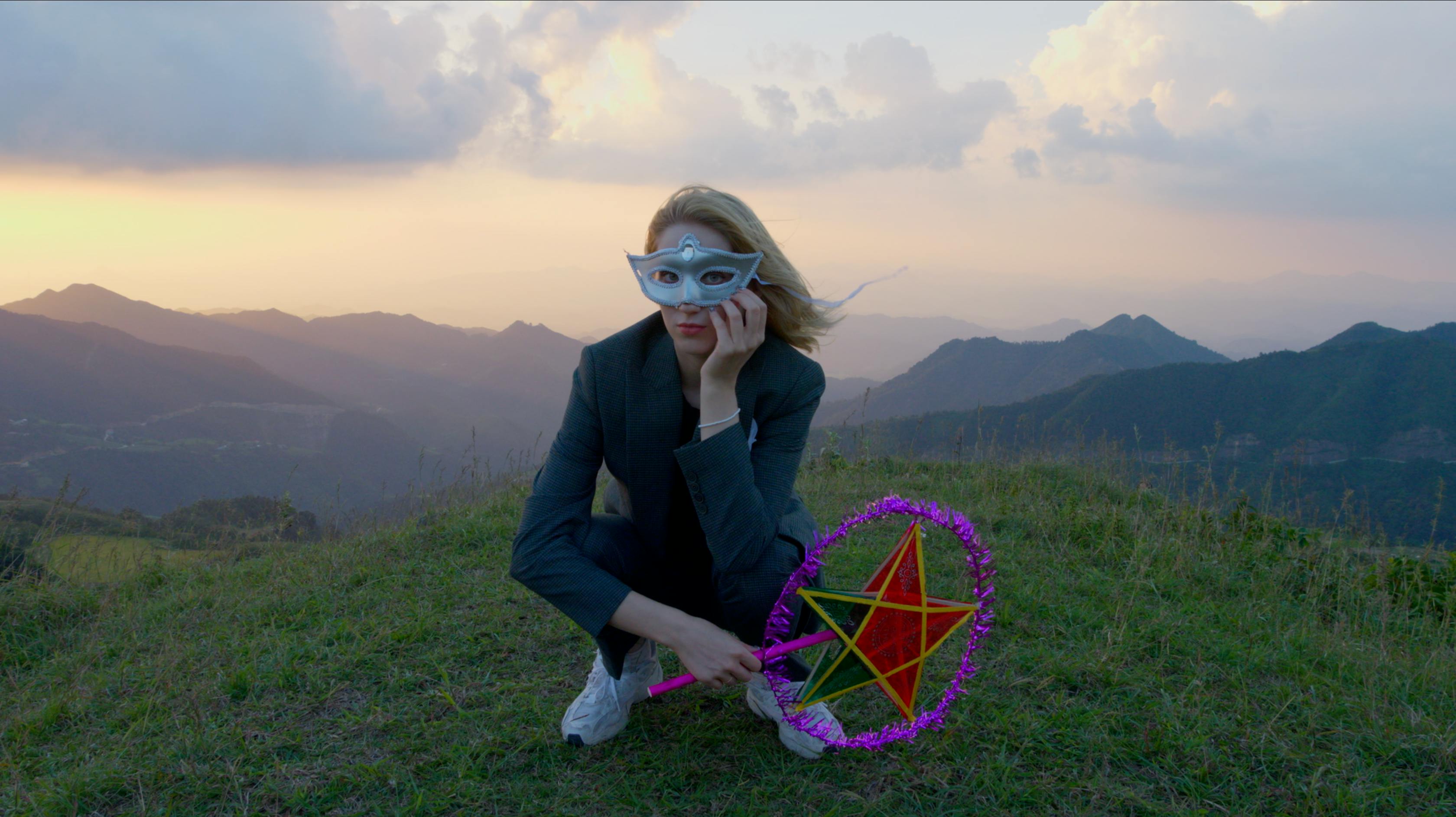 A woman in a mask sitting on a hill with a kite · Free Stock Photo