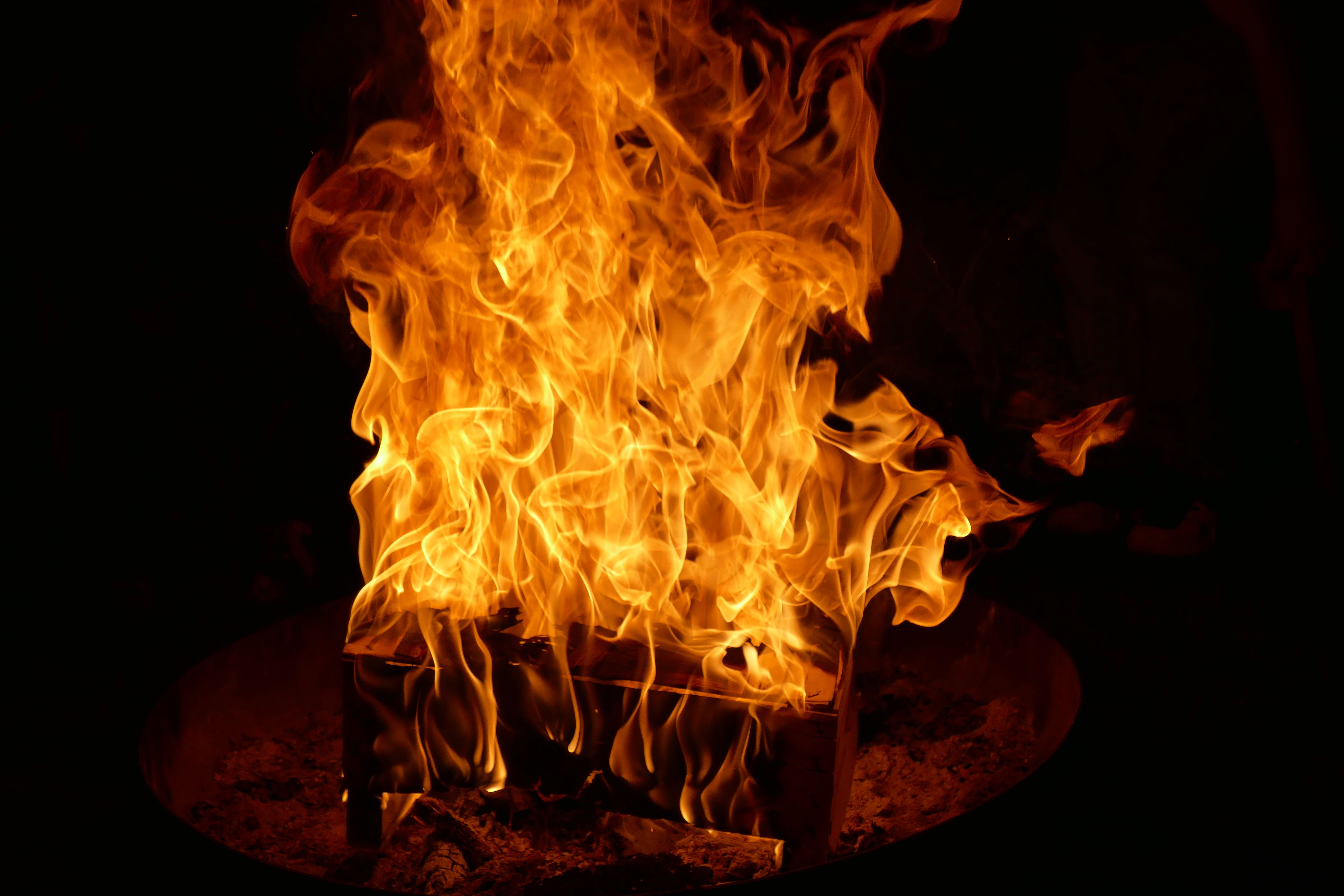 A fire is burning in the dark with a person standing in front of it ...