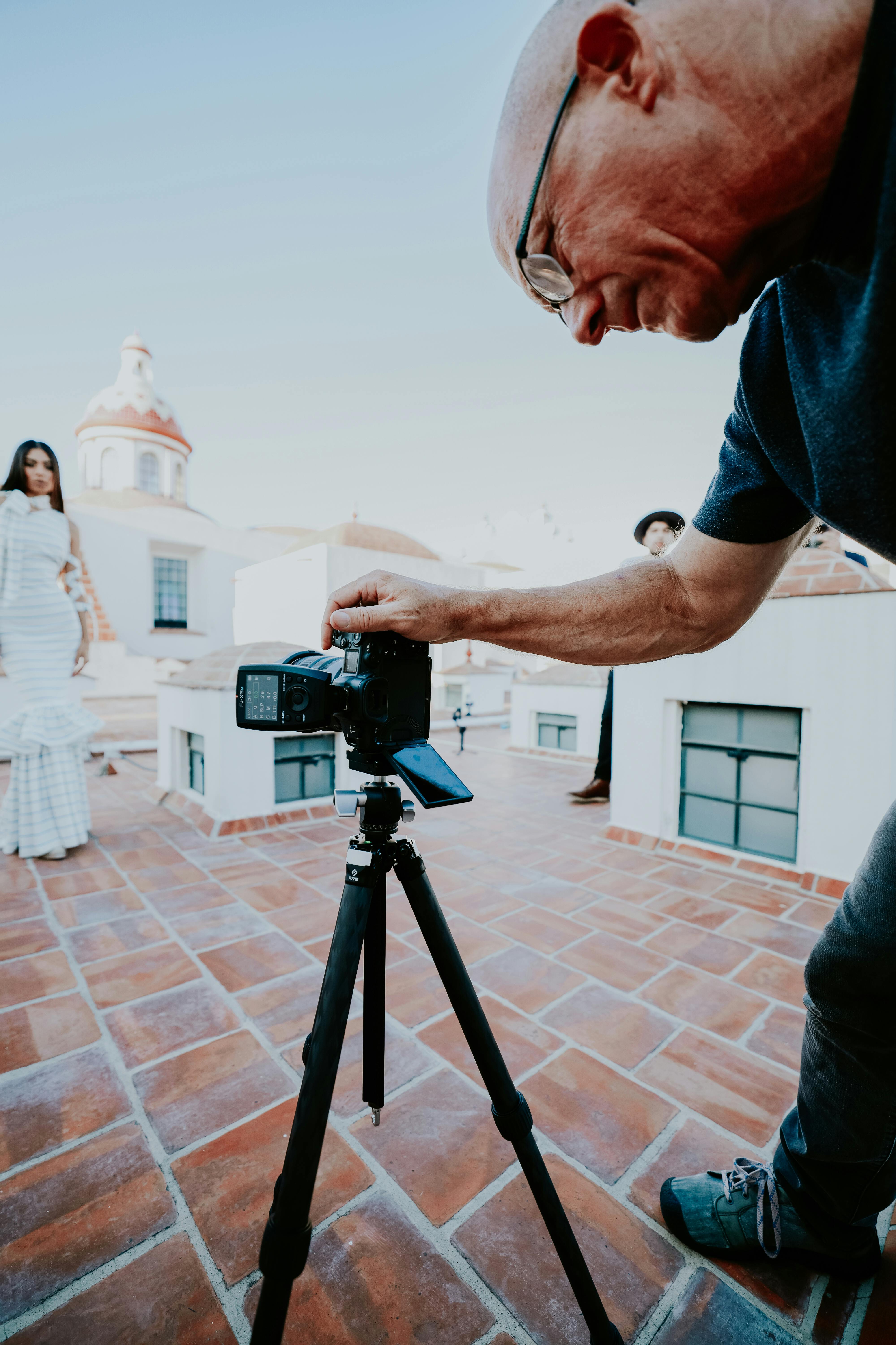 Bald Photographer Setting up Camera for Photo Session · Free Stock Photo