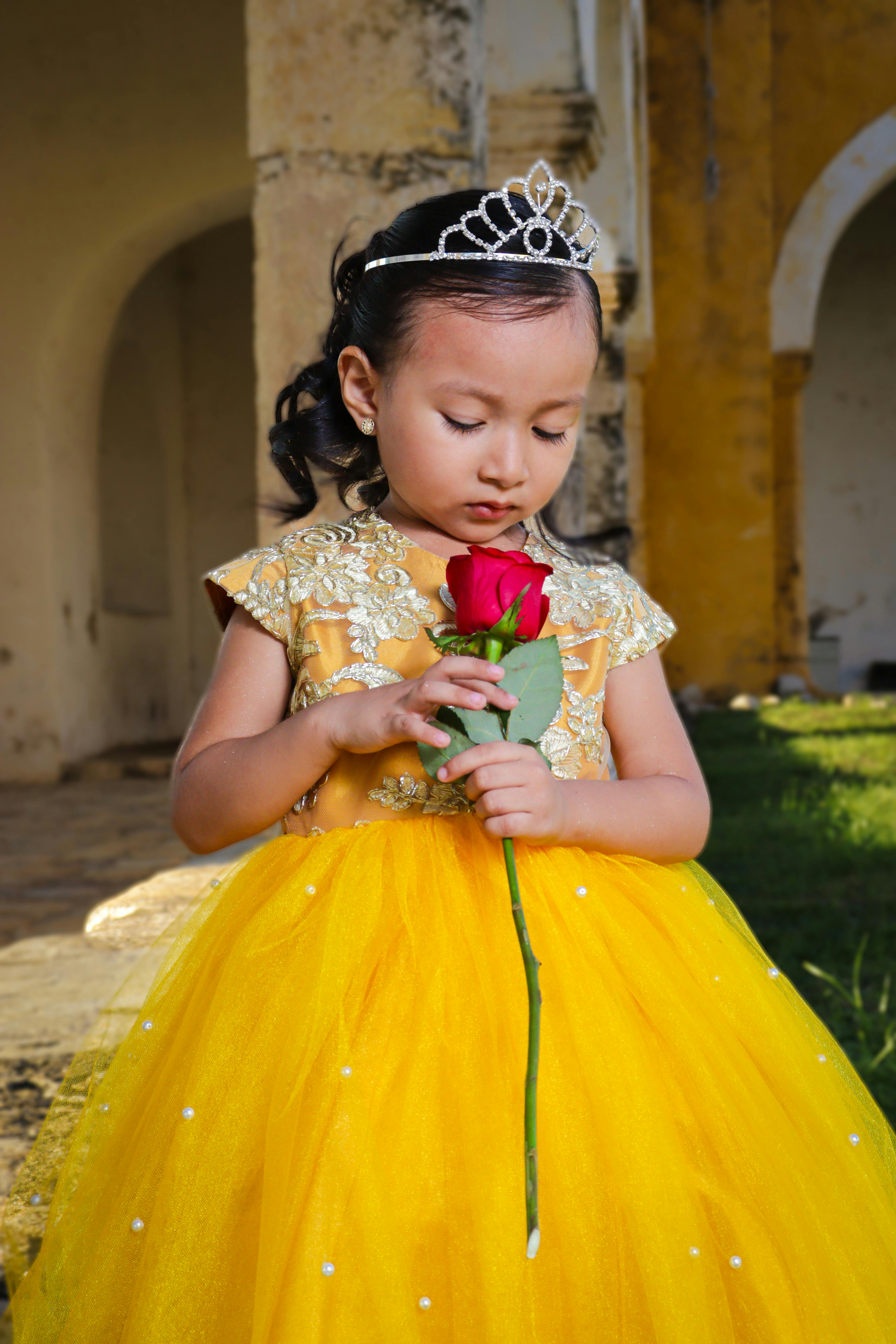 Little Girl in a Yellow Ballgown and Tiara Holding a Rose · Free Stock ...