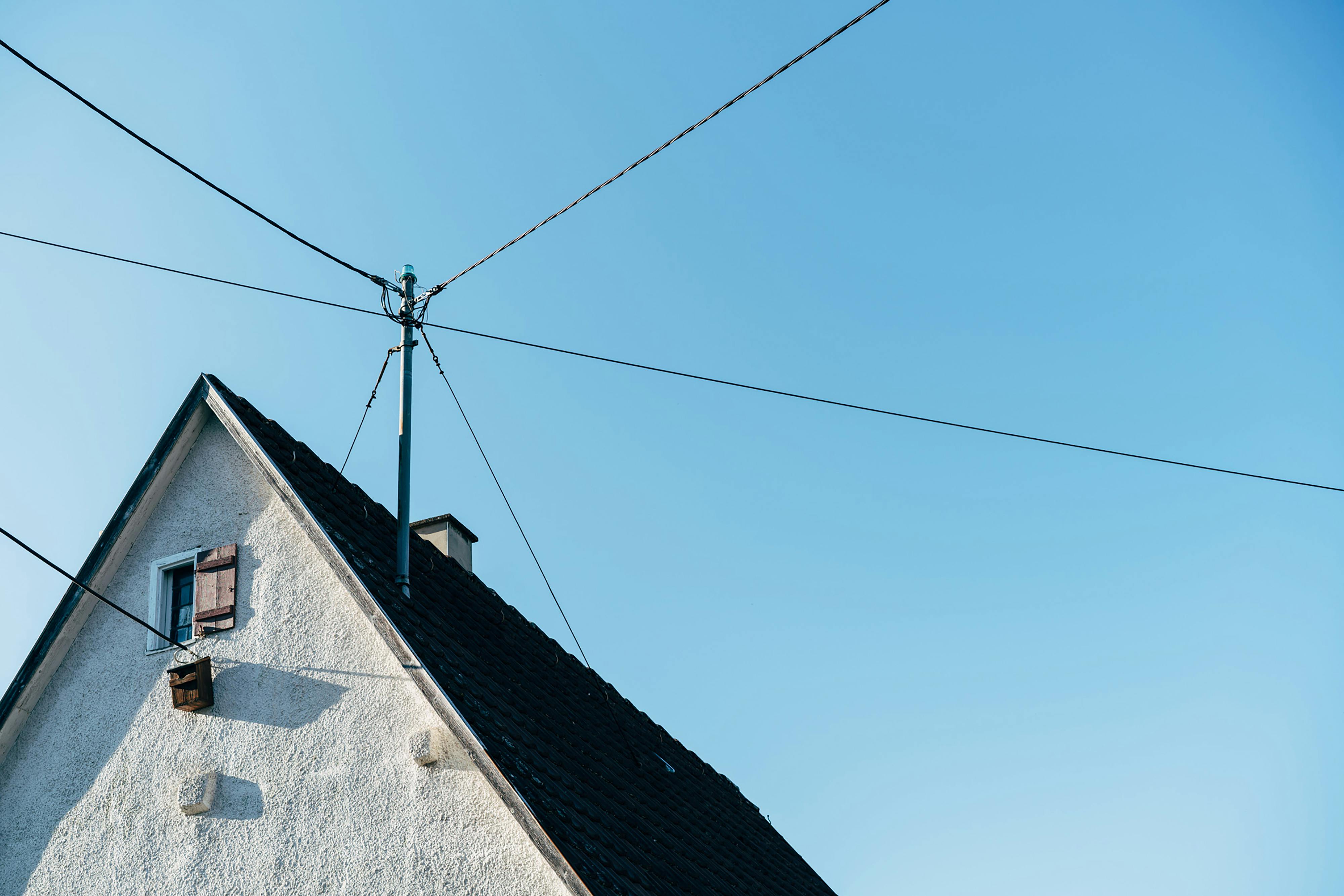 A house with wires and a blue sky · Free Stock Photo