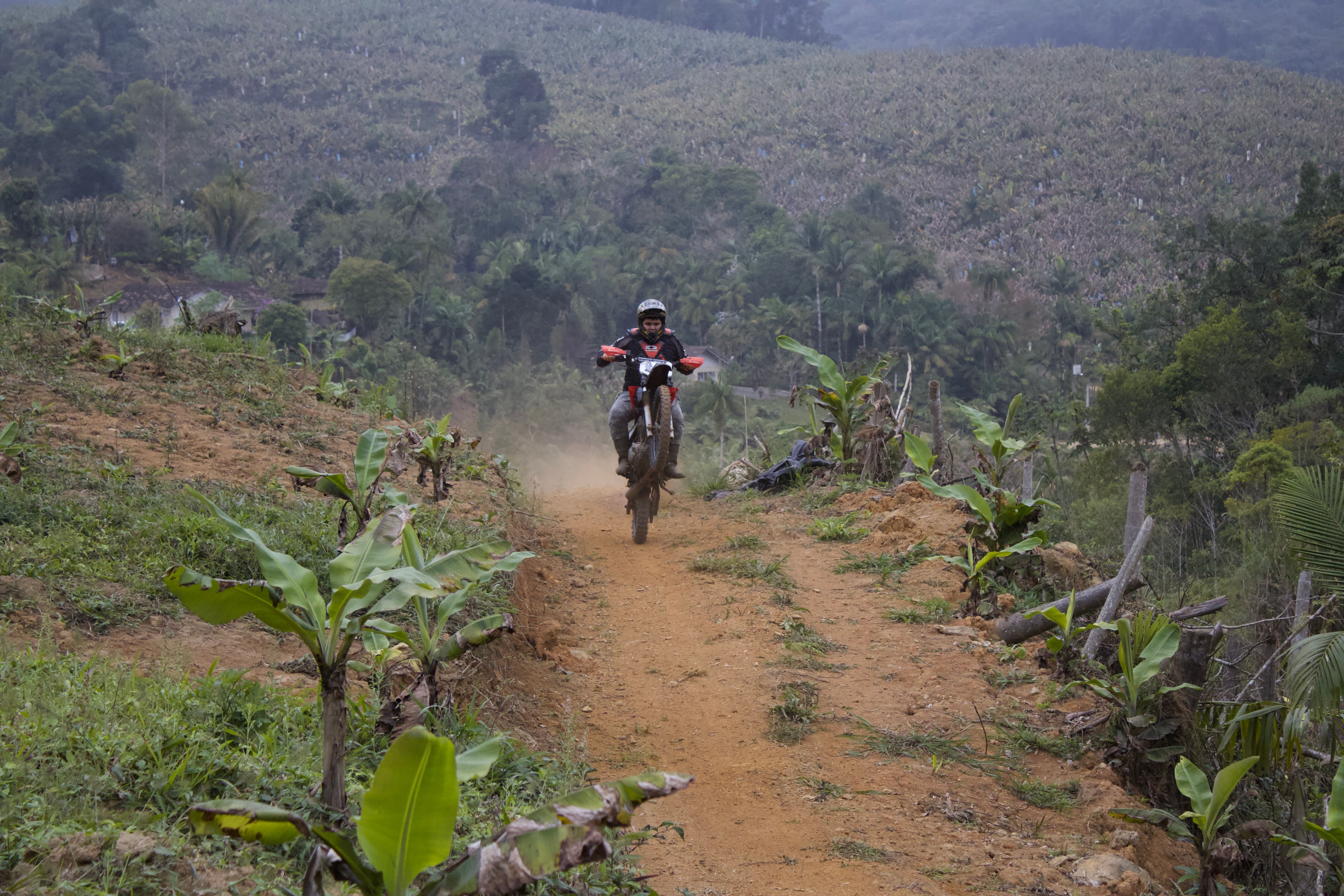 Man Riding Motocross on Dirt Road in Village · Free Stock Photo