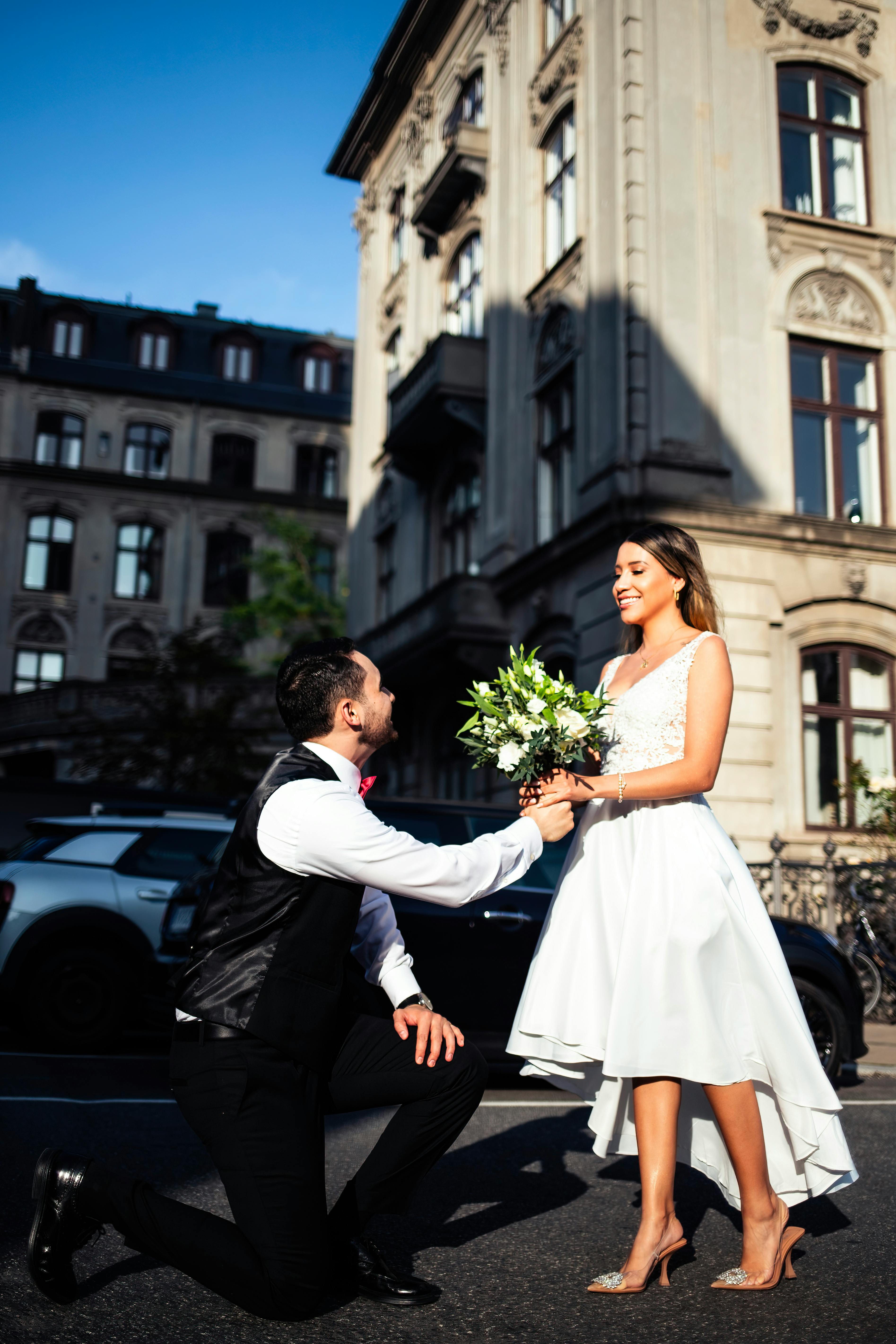 A man kneeling down to propose to a woman in the street · Free Stock Photo