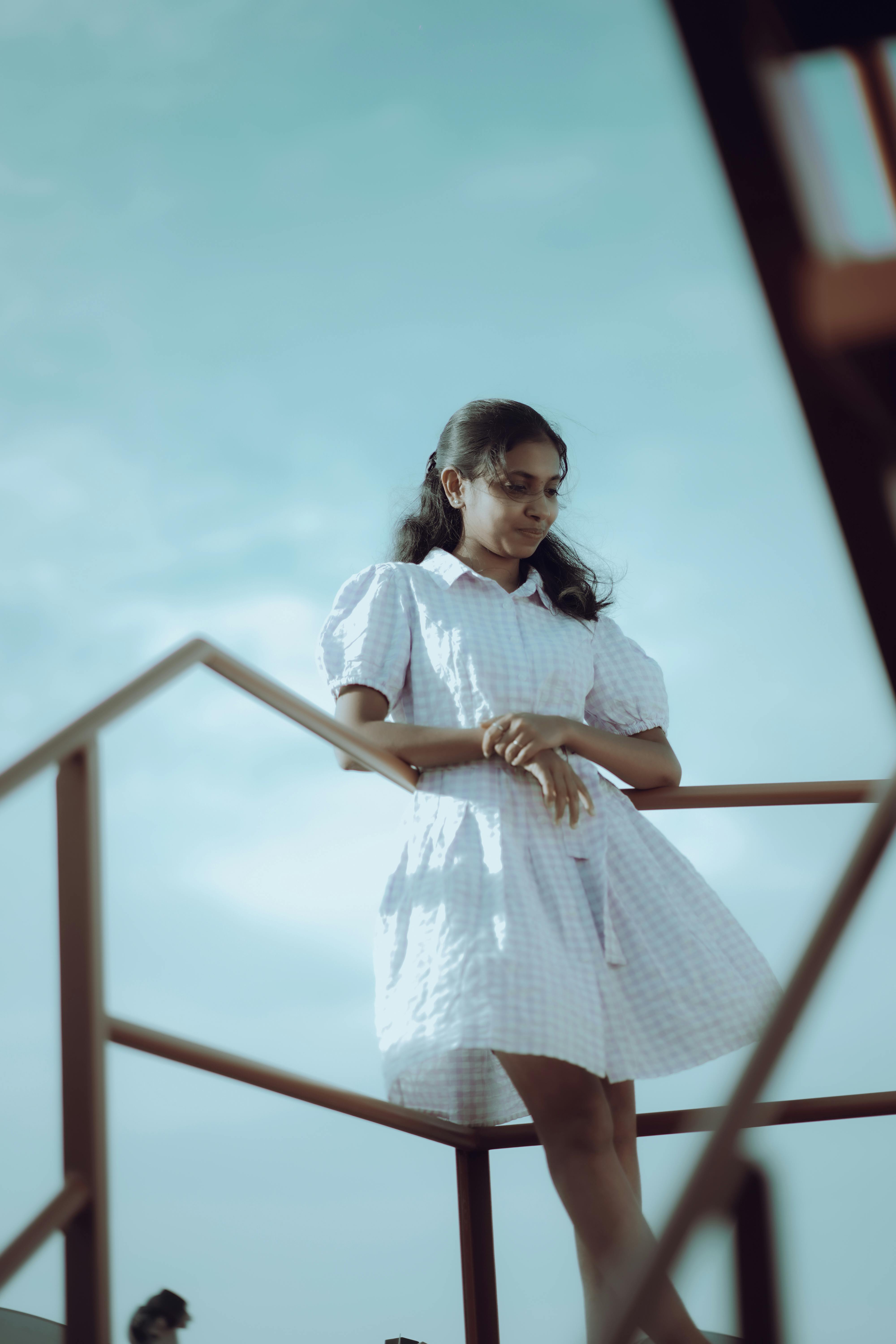 Girl in White Summer Dress Leaning on the Railing against the ...