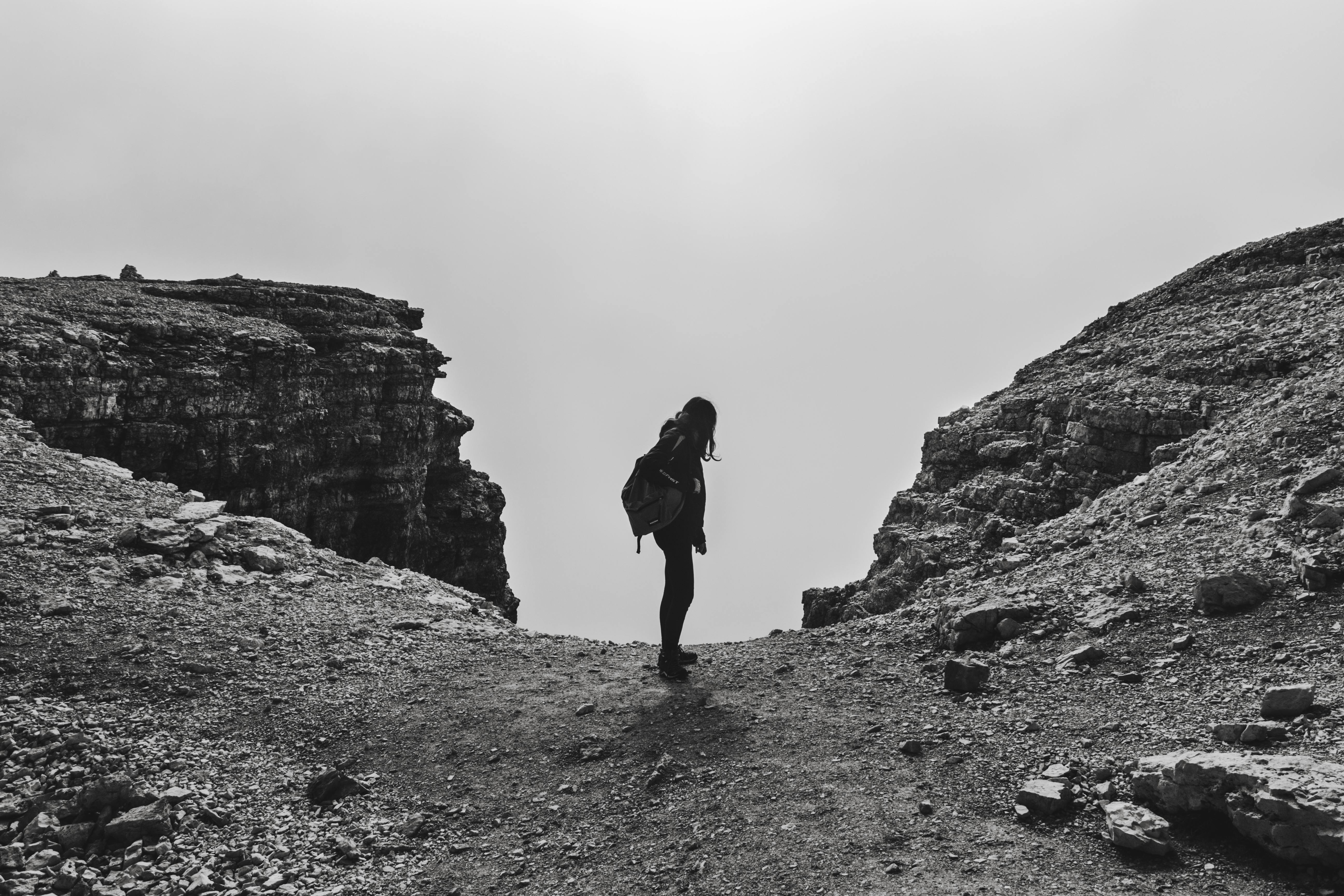 Hiker Looking into the Abyss from the Edge of a Rock · Free Stock Photo